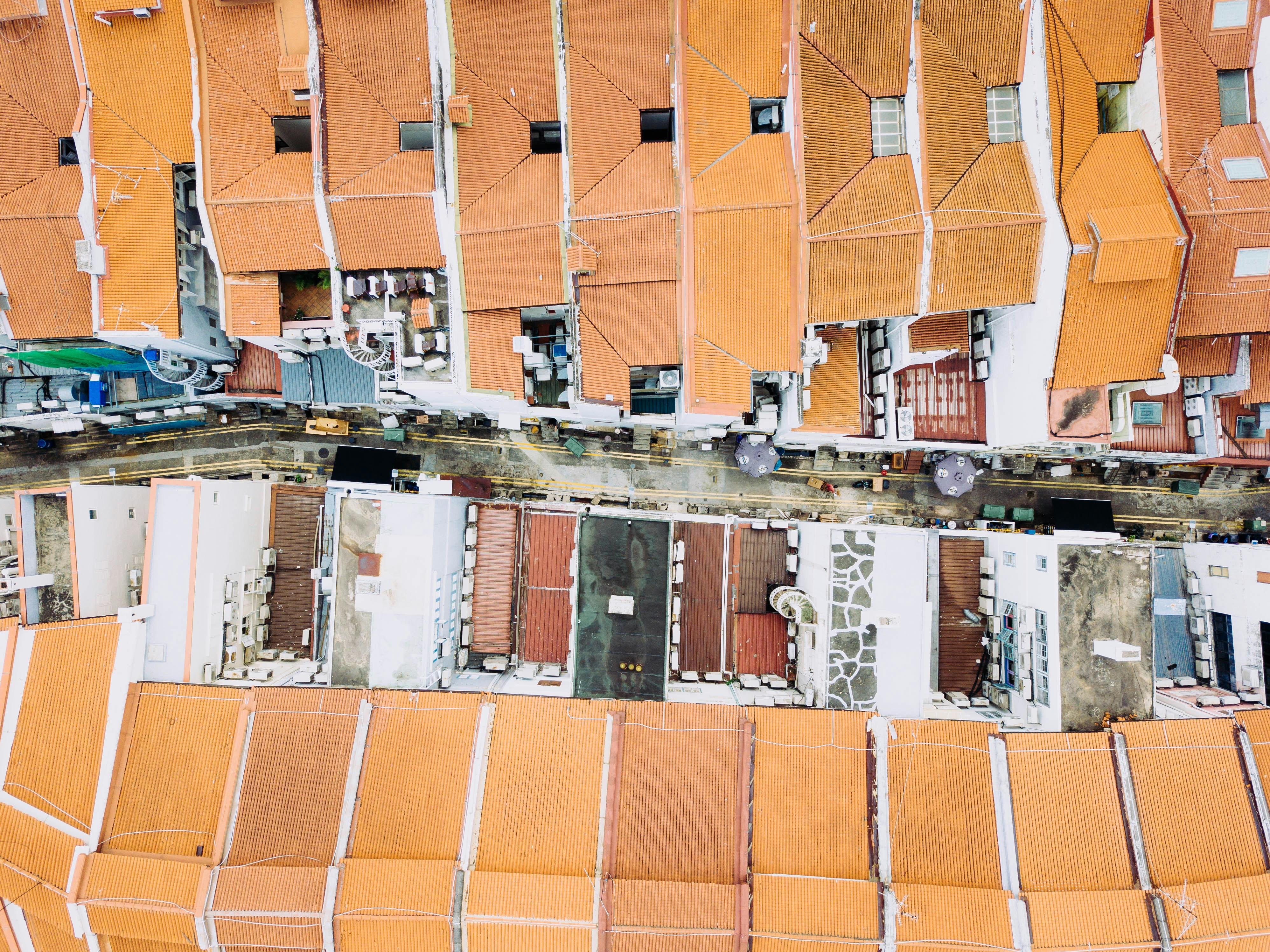 Aerial perspective revealing a maze of terracotta rooftops interspersed with narrow streets and modern architecture. The layout highlights the contrast between traditional and contemporary urban elements.