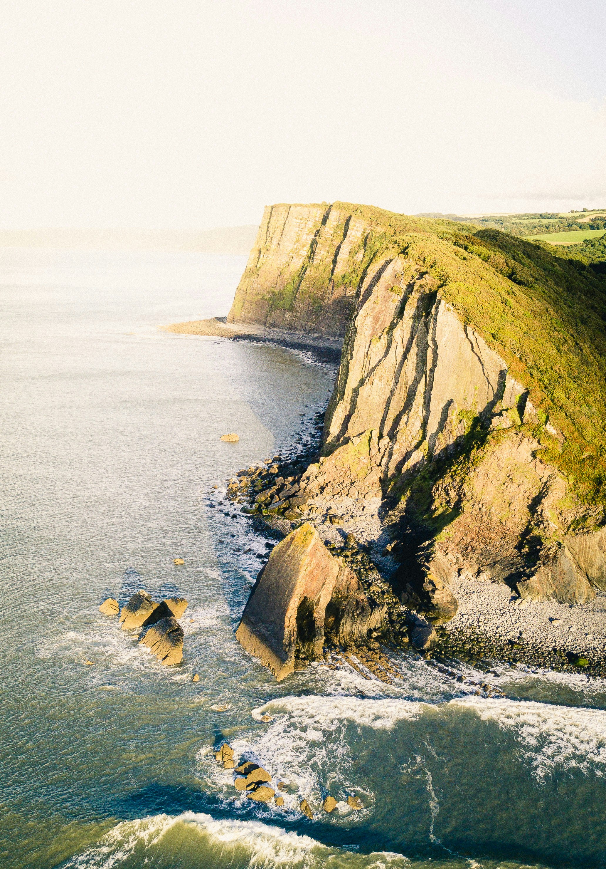 Jagged cliffs meet the ocean's embrace, revealing the intricate patterns of nature's artistry. The rocky shoreline is accentuated by gentle waves lapping against the stones.