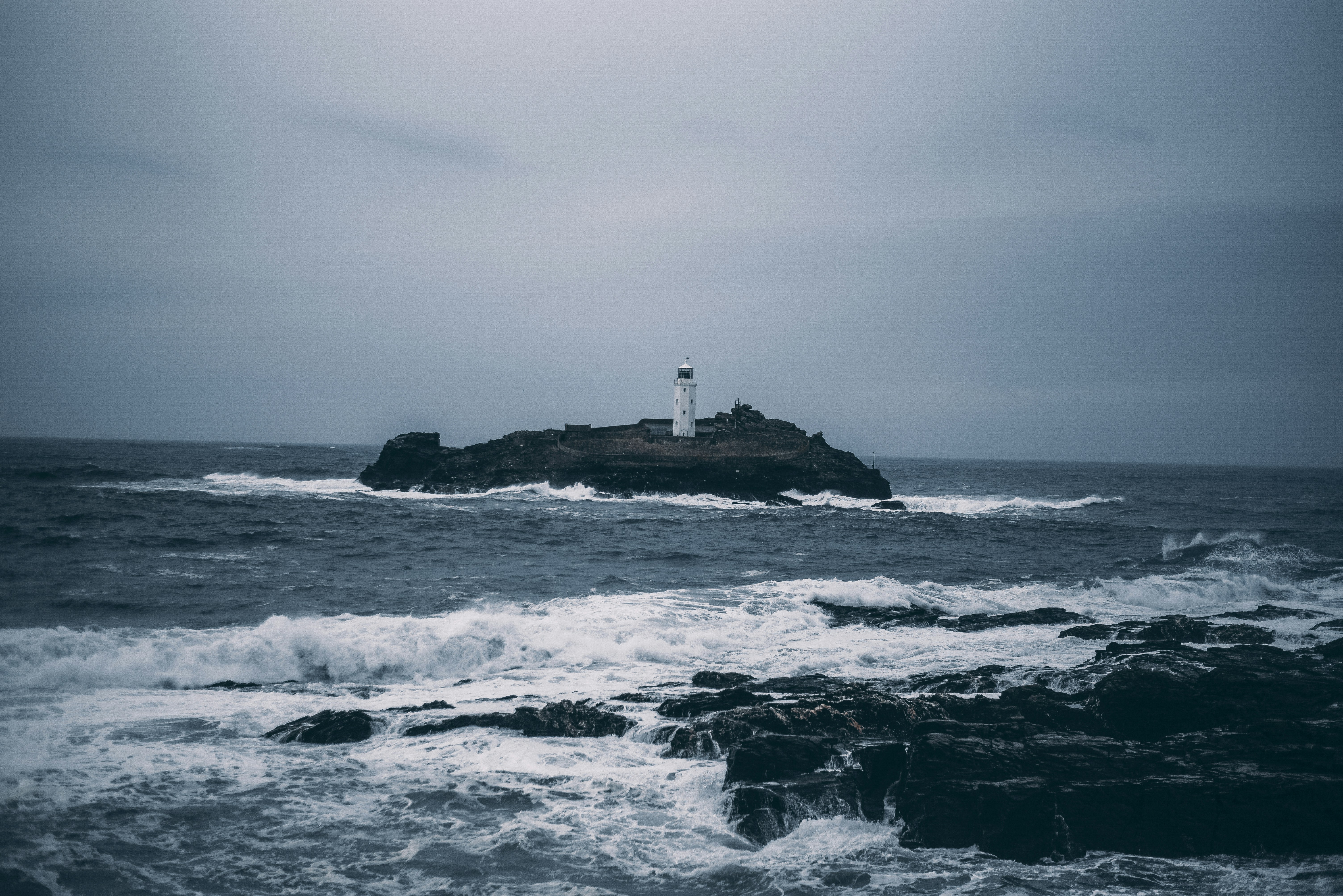 White lighthouse on rock formation surrounded by ocean photo – Free ...