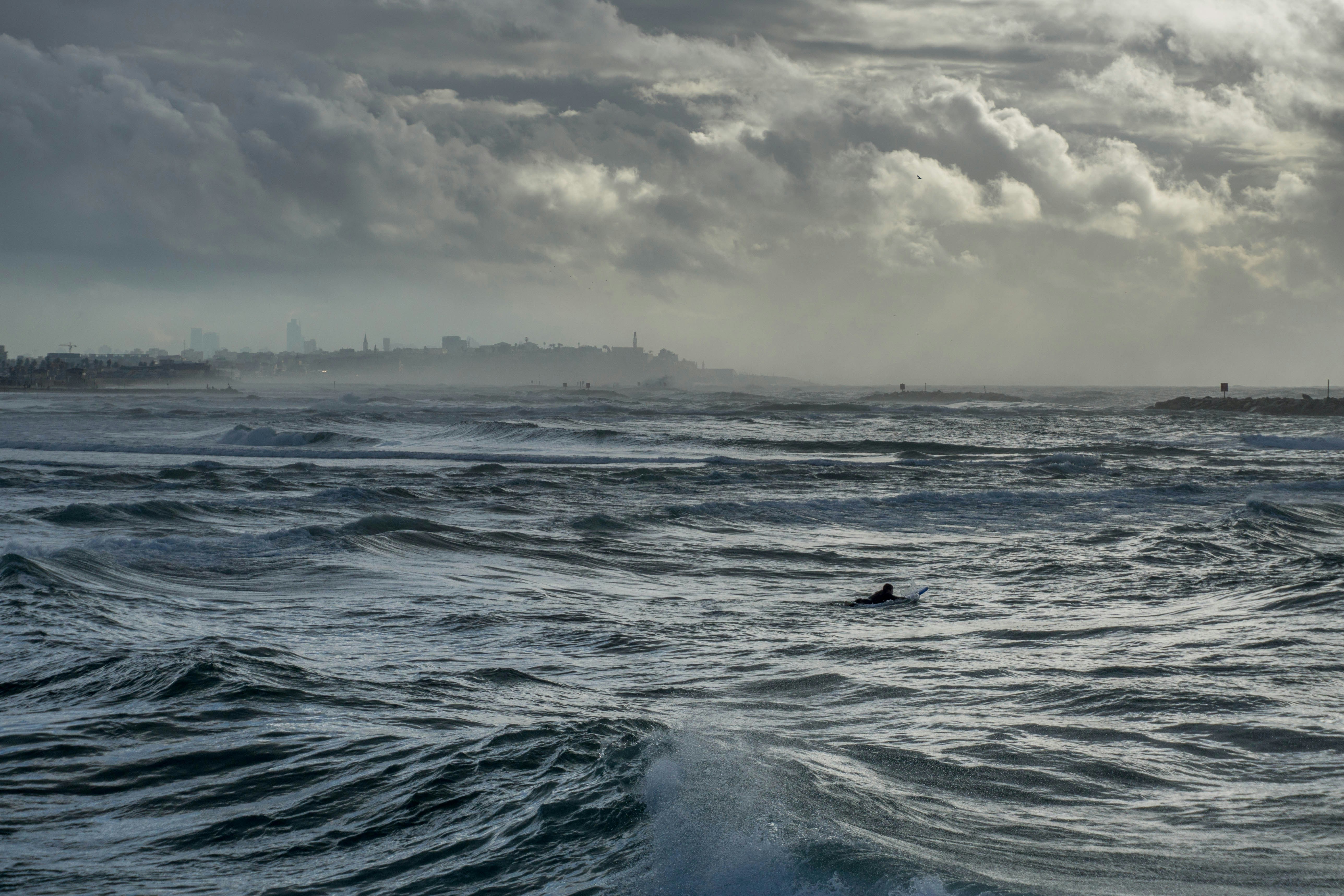 Choppy ocean waves roll beneath a dramatic, cloud-laden sky.