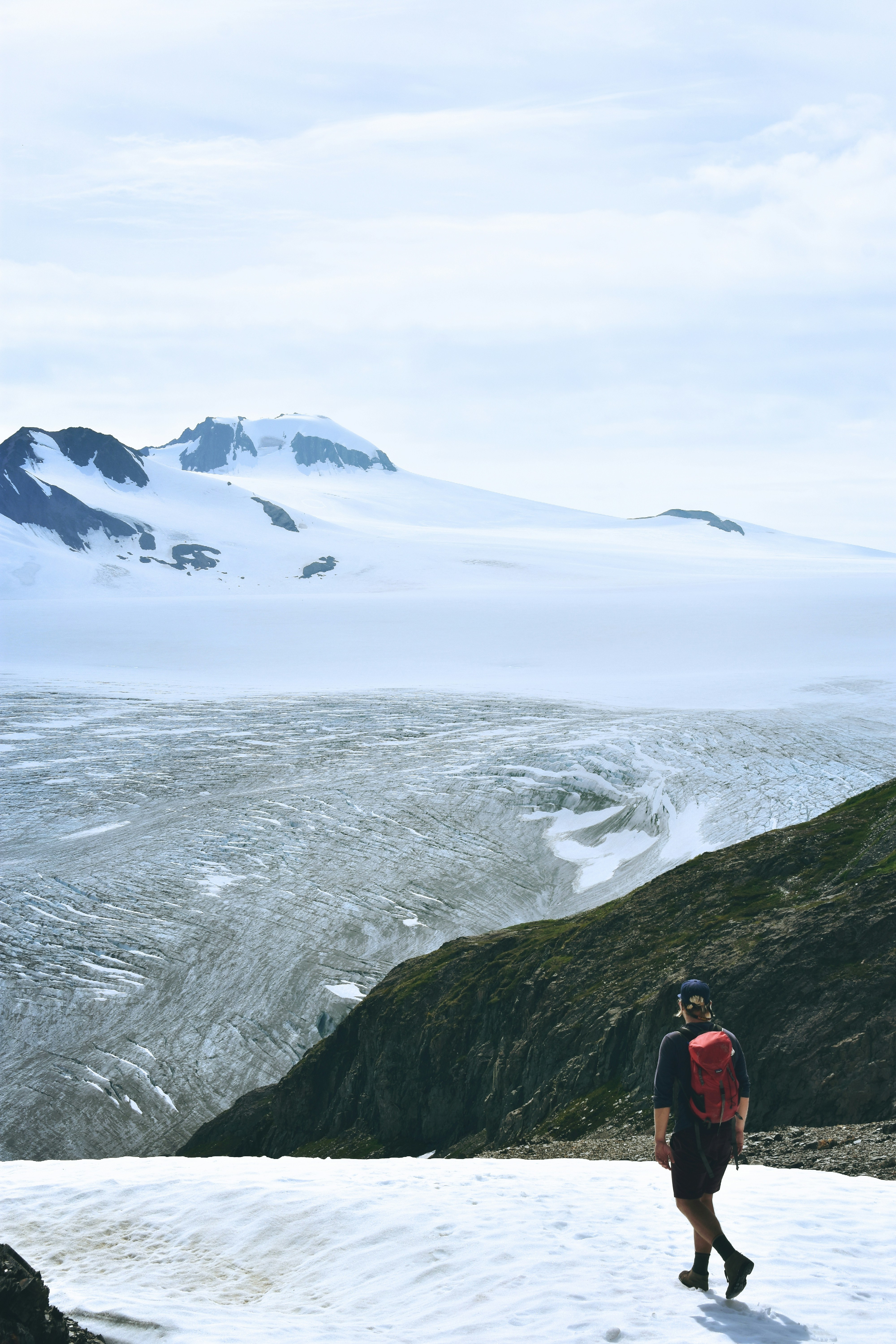 Red Backpack at the Glacier Edge: a lone hiker against a vast alpine icefield