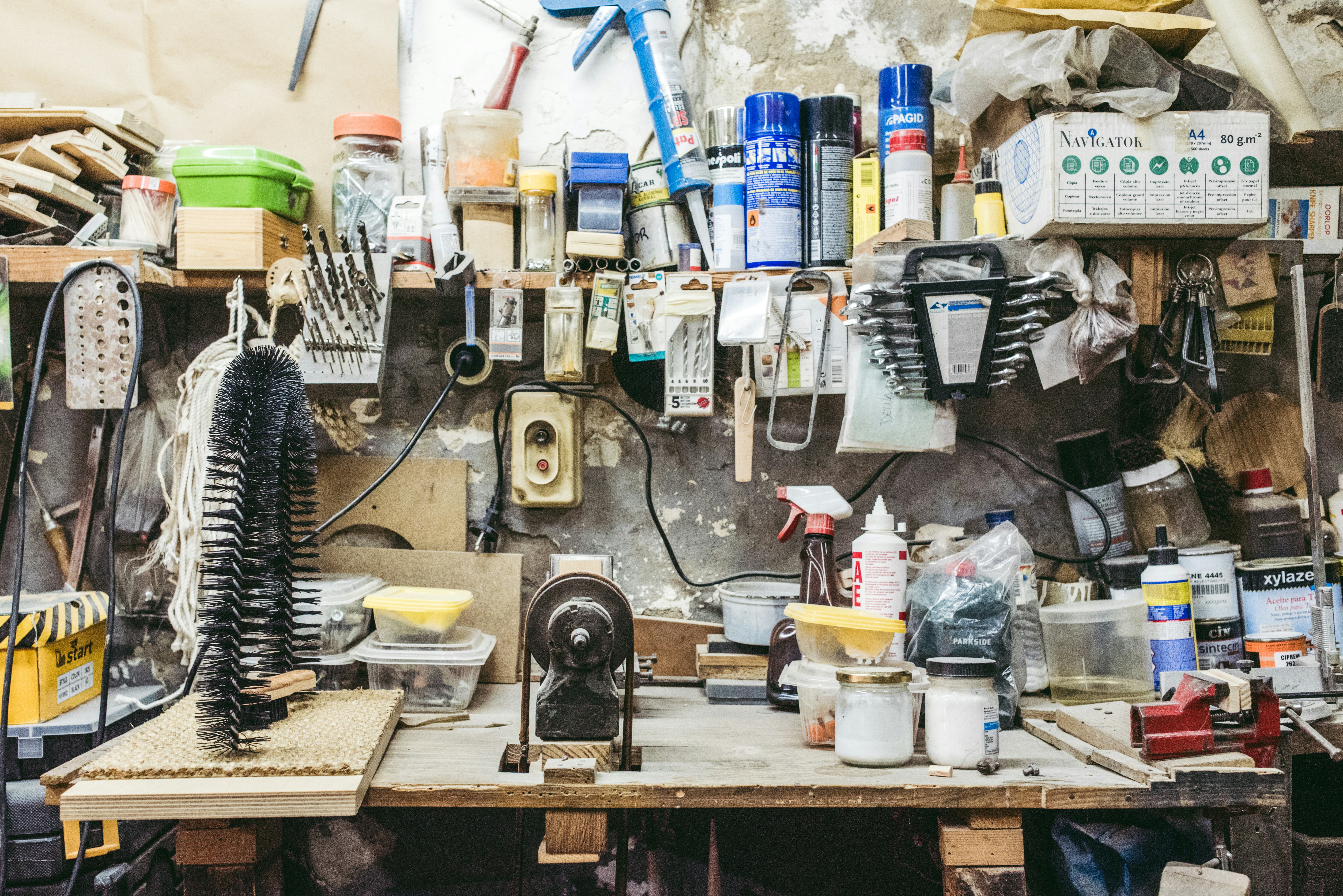 Cluttered workbench filled with tools, containers, and supplies in a busy workshop.