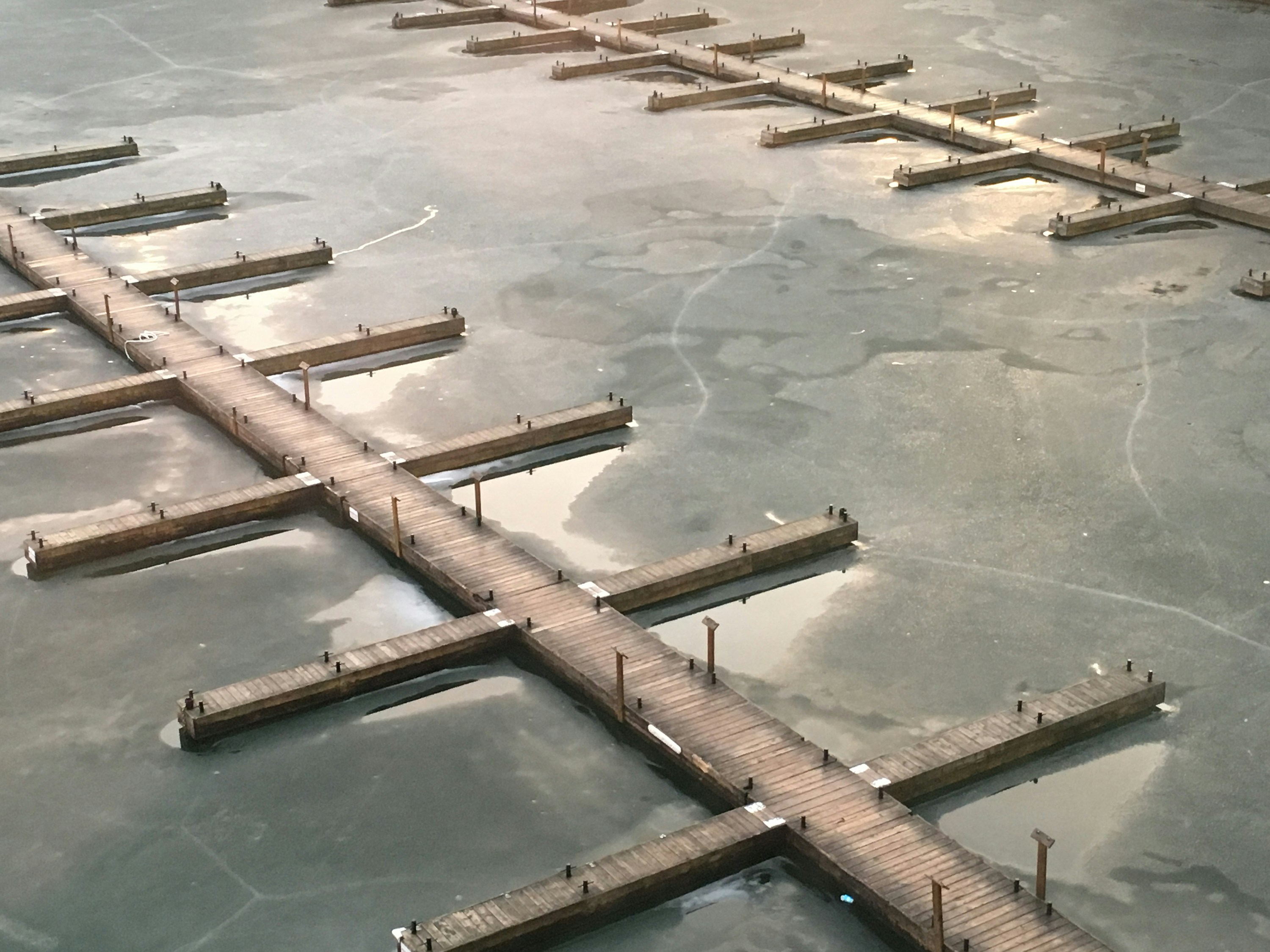 Snow-dusted pier extends over an icy lake under soft, diffused light.