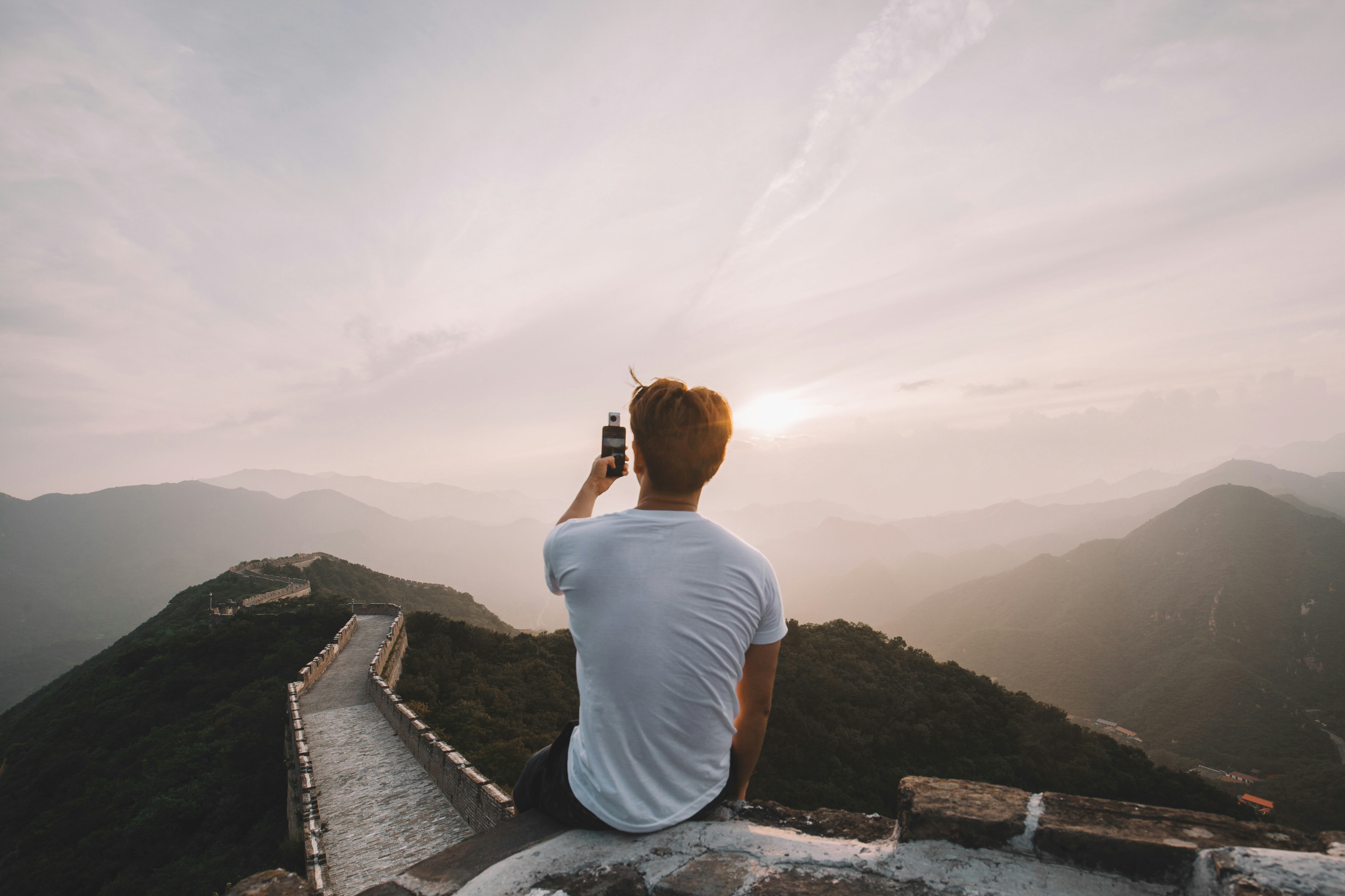 Man sitting on cliff facing mountains photo – Free China Image on Unsplash