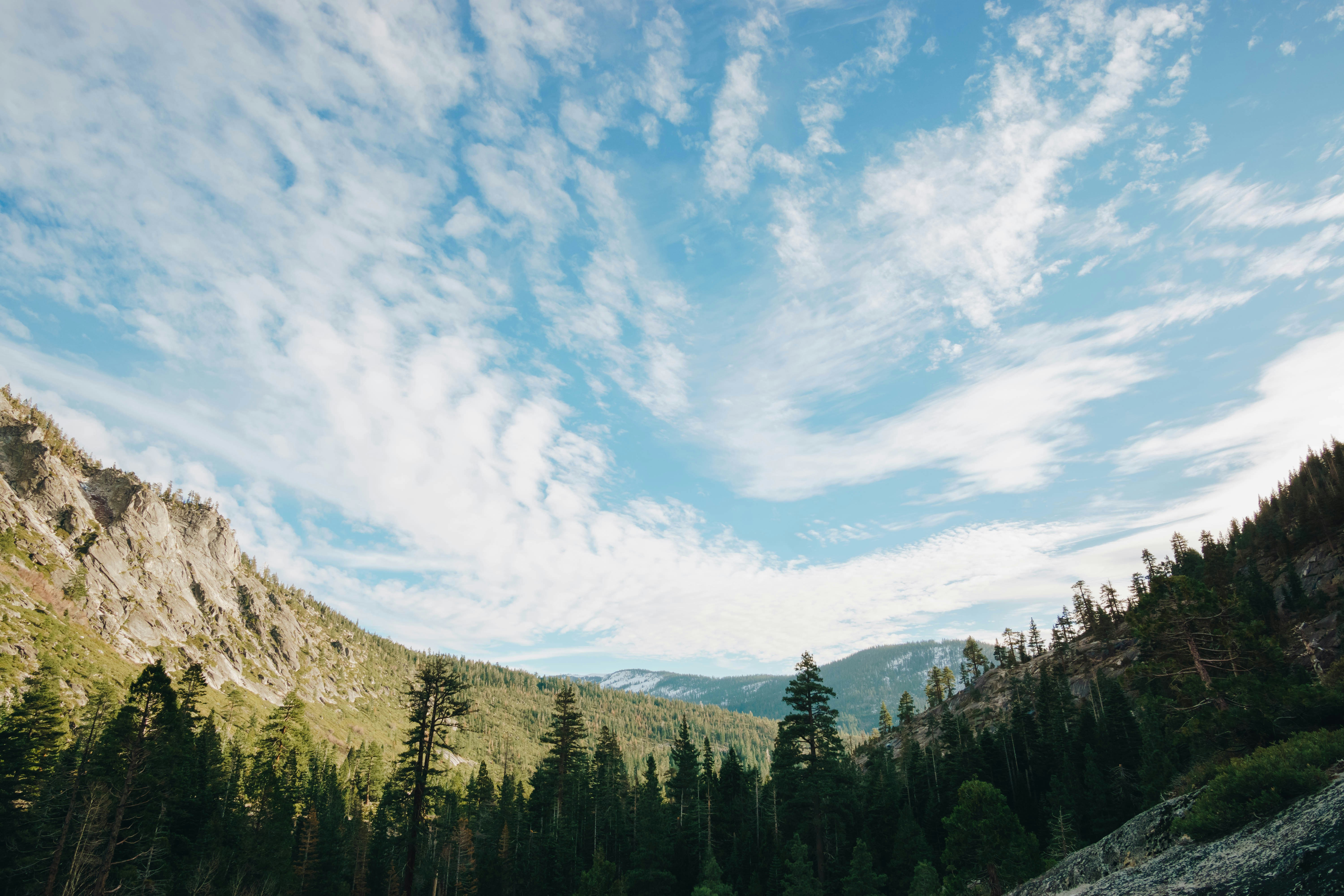 Vast sky with scattered clouds over forested mountain landscape.