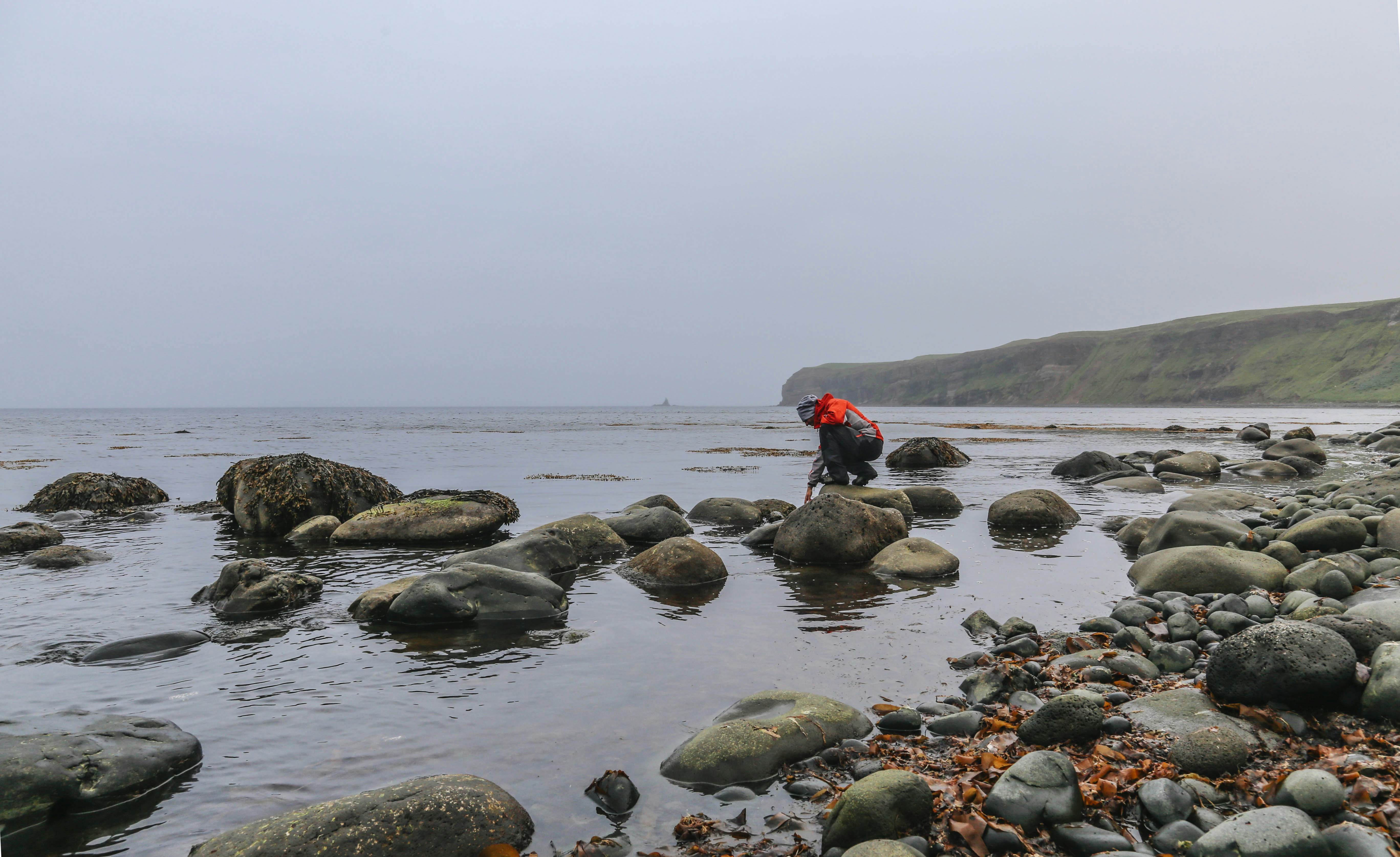 Persona agachada en roca roca cerca del cuerpo de agua foto – Imagen de ...