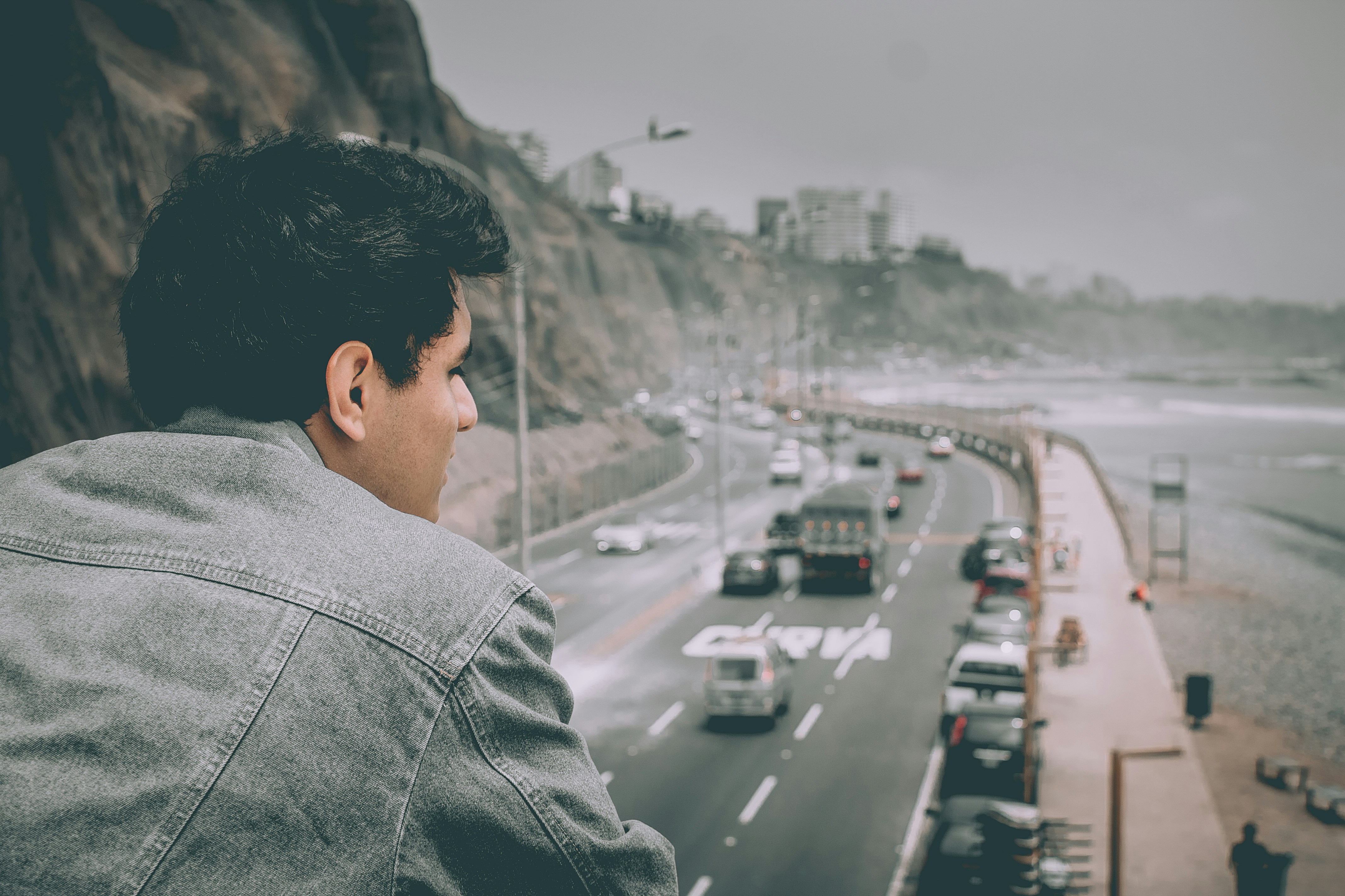 A man looking out over a highway filled with traffic photo – Free Grey ...