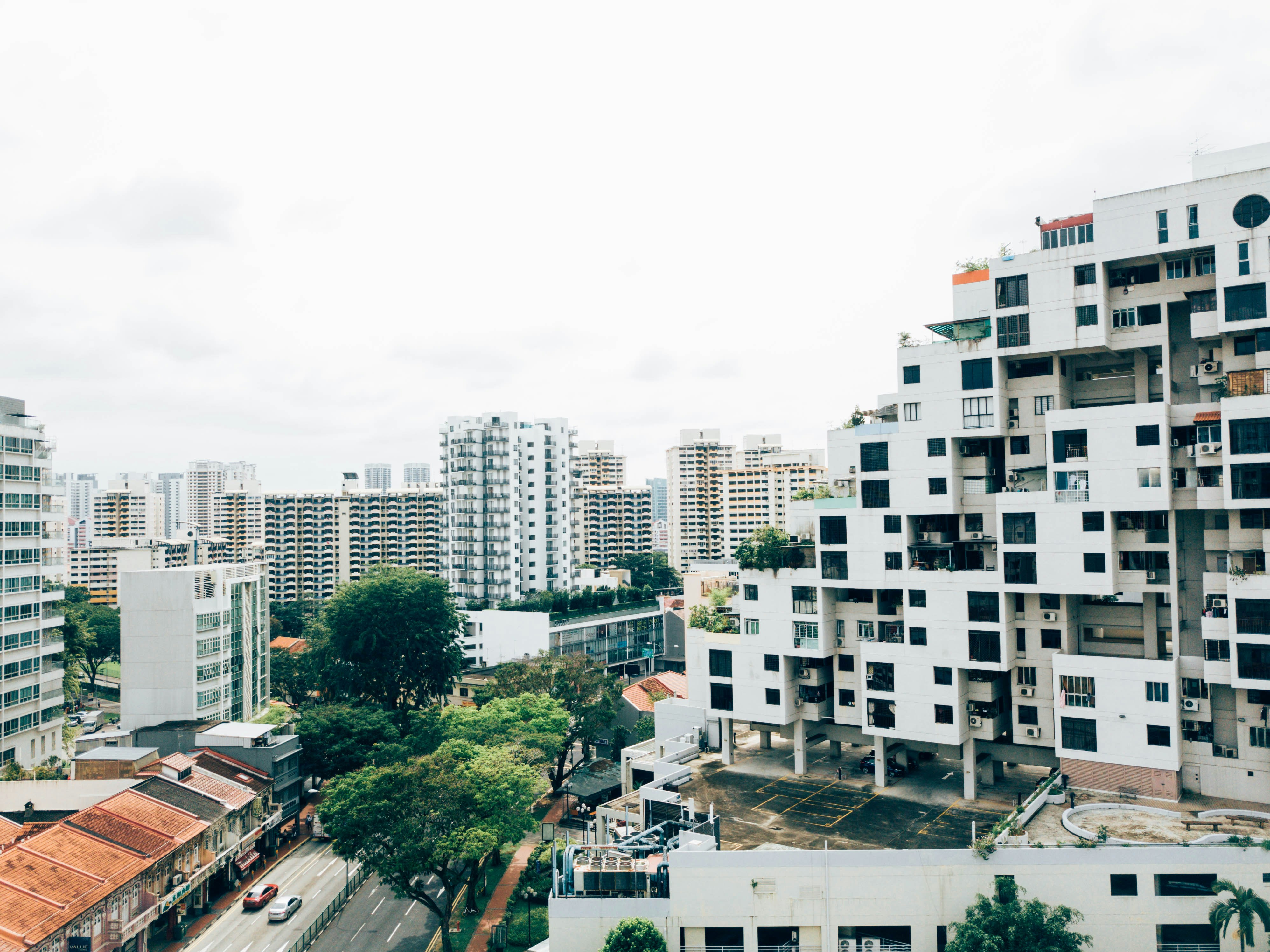 White concrete building near road and tree under cloudy sky at daytime ...