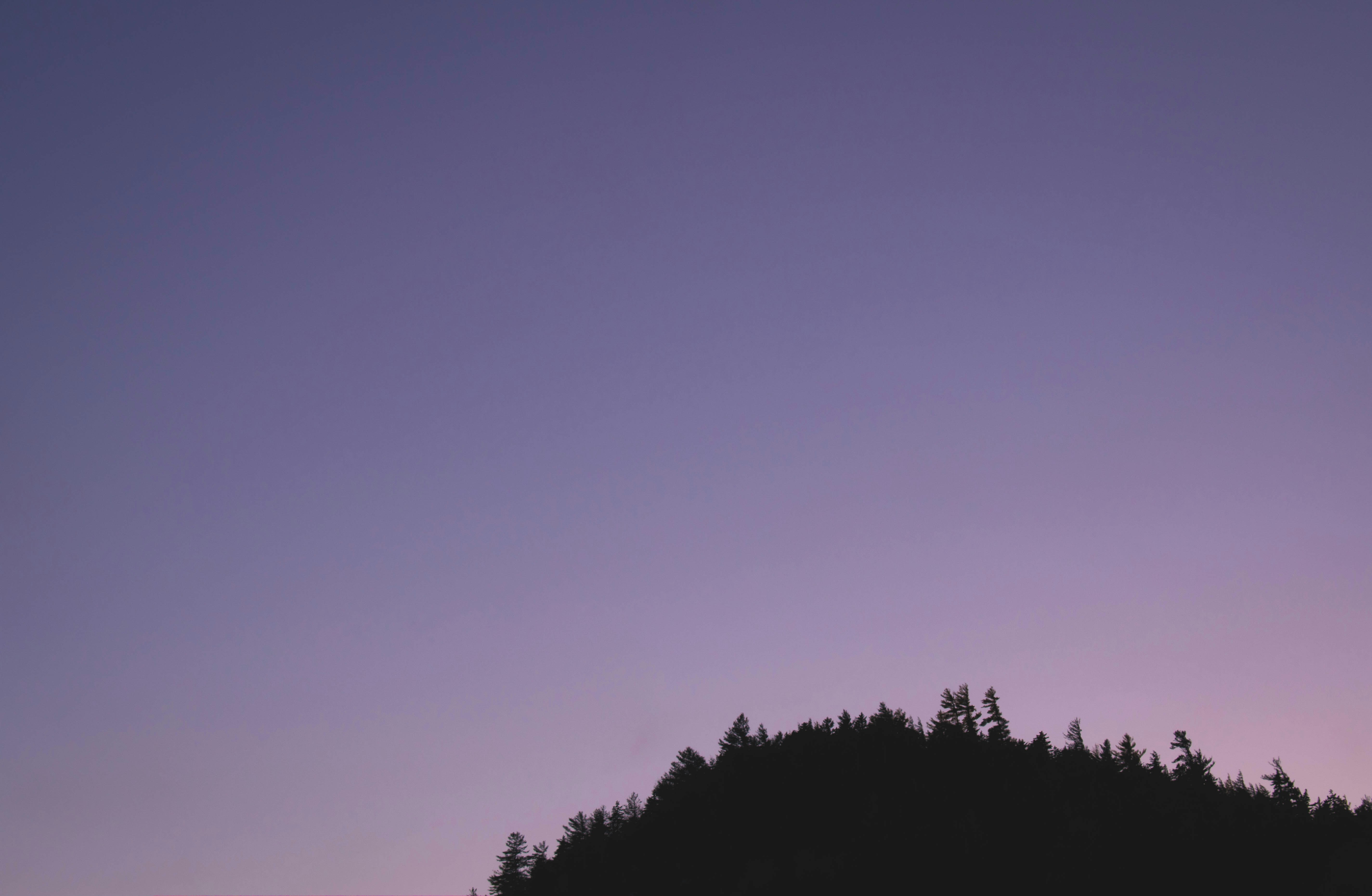 Silhouette of a mountain ridge under a purple-hued dusk sky.