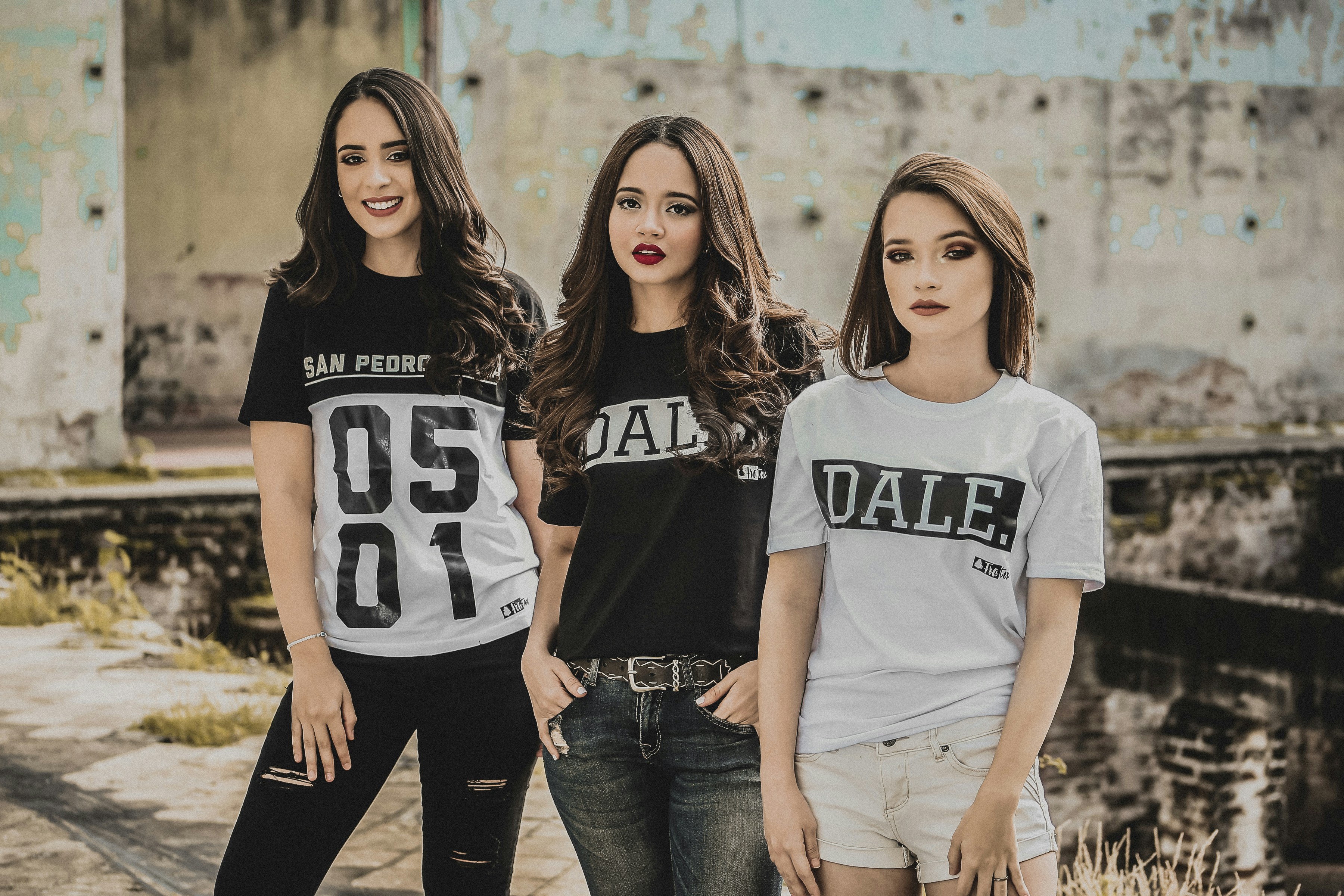 Three models showcase trendy graphic tees in an urban setting, highlighting contemporary fashion aesthetics and diverse styles.