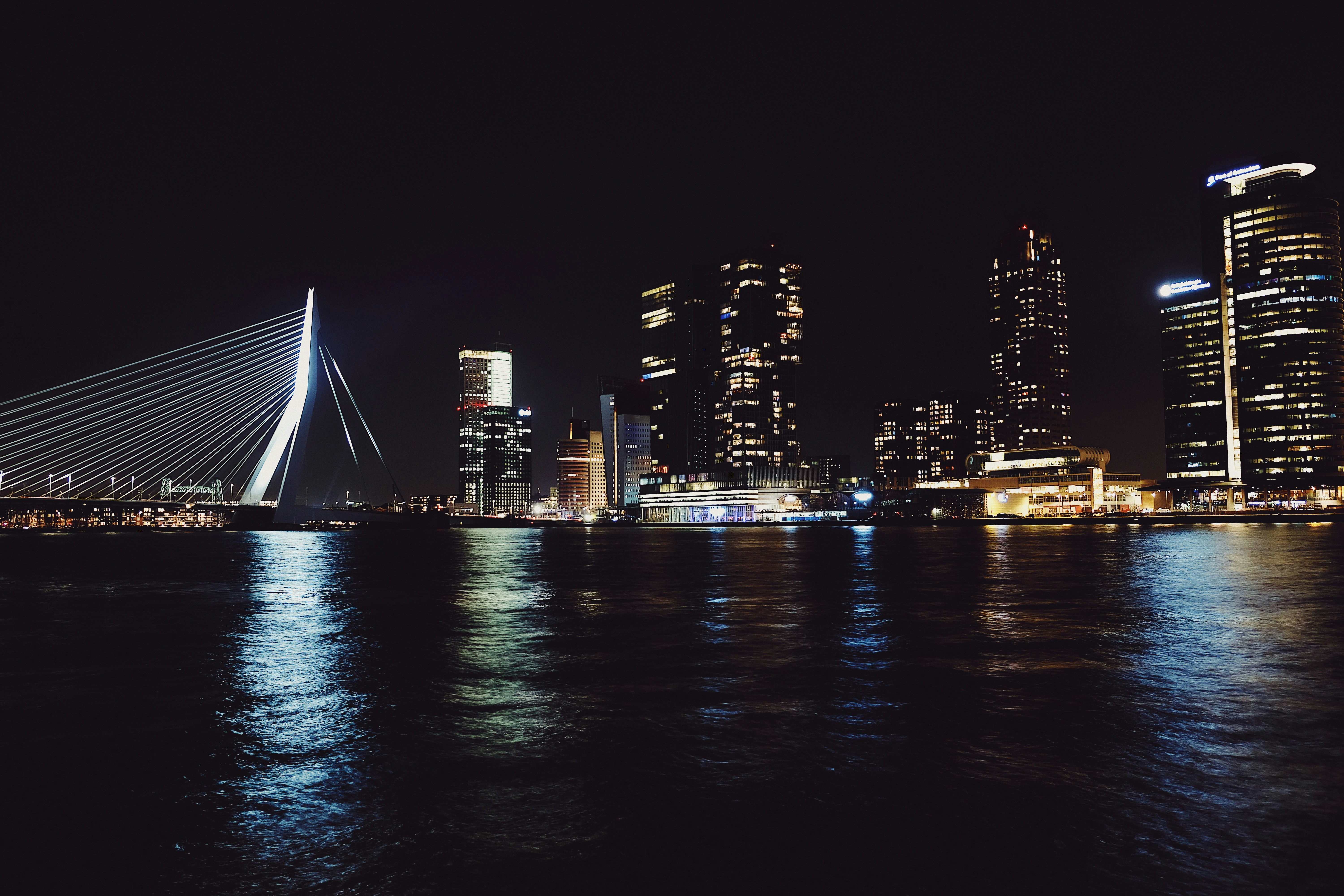 Illuminated Rotterdam skyline with reflections on the river at night.
