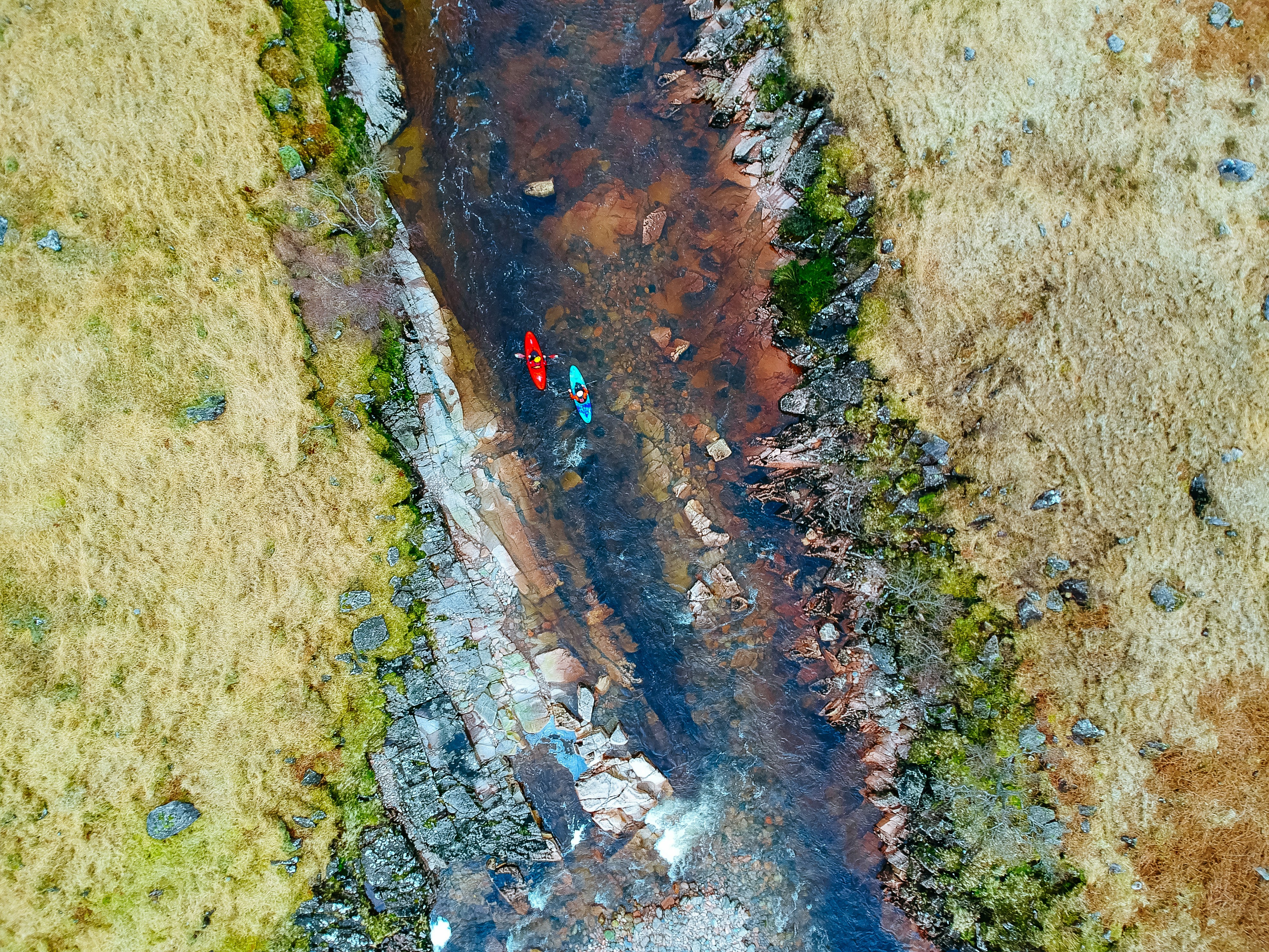Red and Blue Kayaks Thread a Rocky Ribbon Through a Golden Moorland Gorge