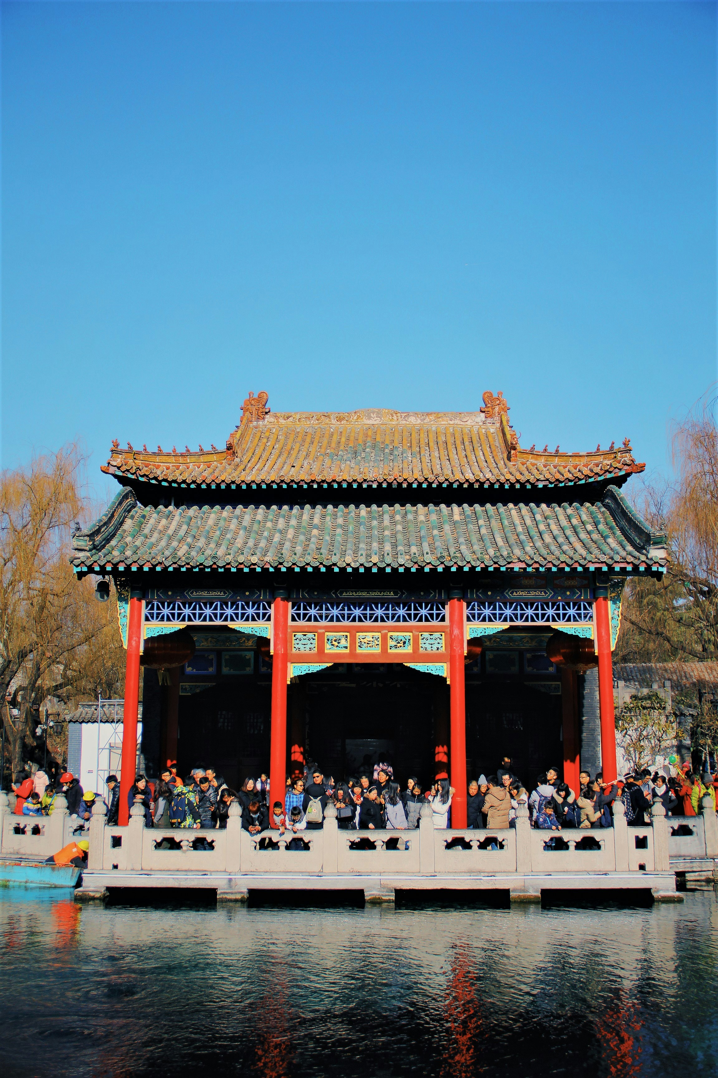Pavilion Over the Quiet Lake: Red Columns, Blue Sky, and a Crowded Terrace