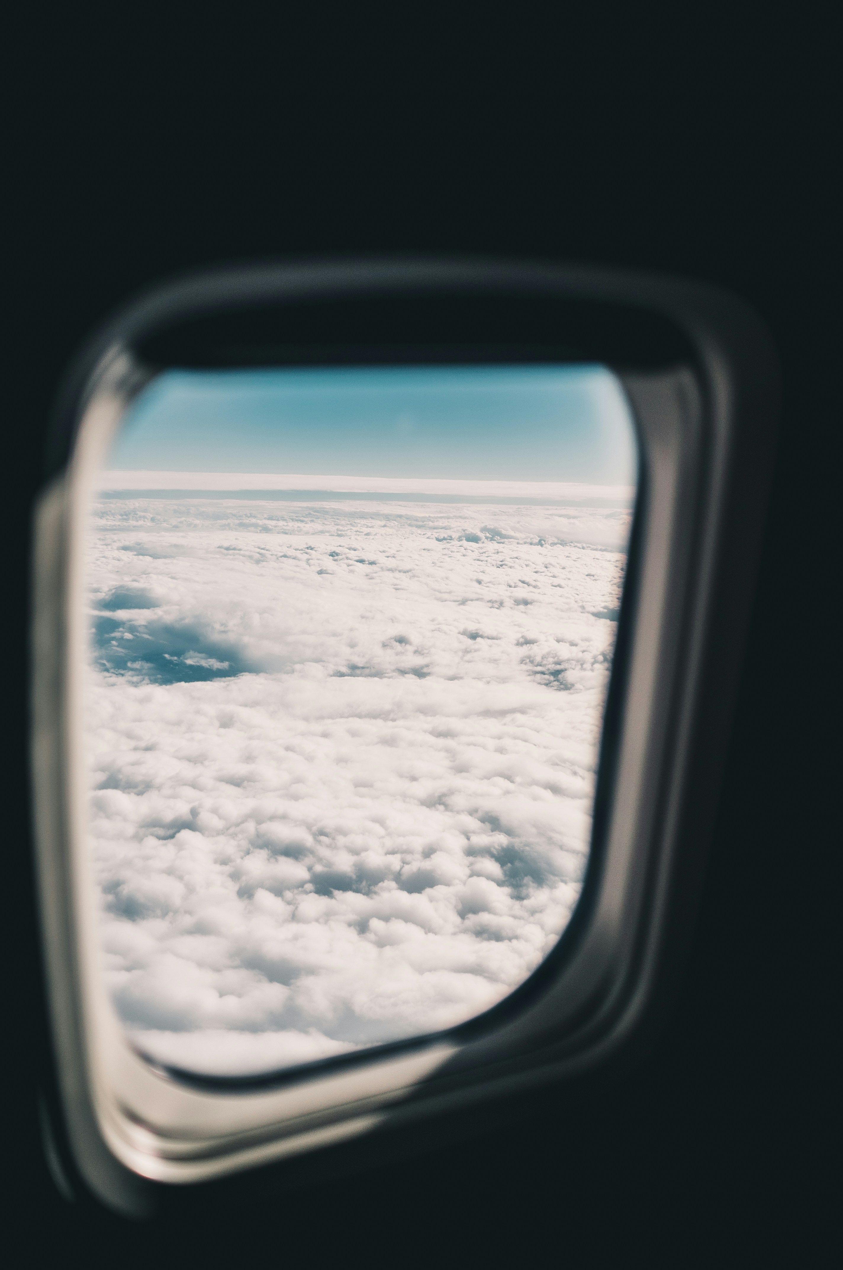 View from an airplane window showcasing a vast expanse of fluffy clouds under a clear blue sky.
