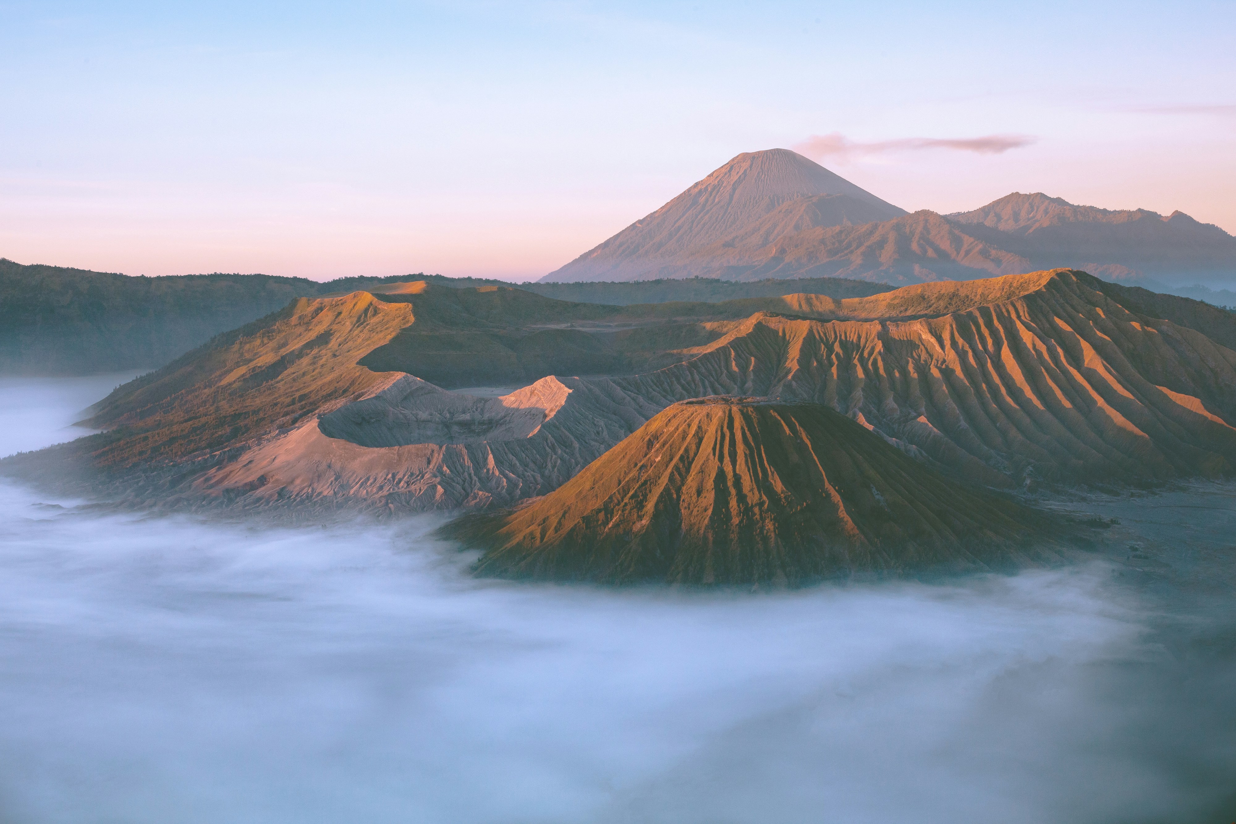 Volcanic peaks of Mount Bromo emerging from a sea of clouds at sunrise.
