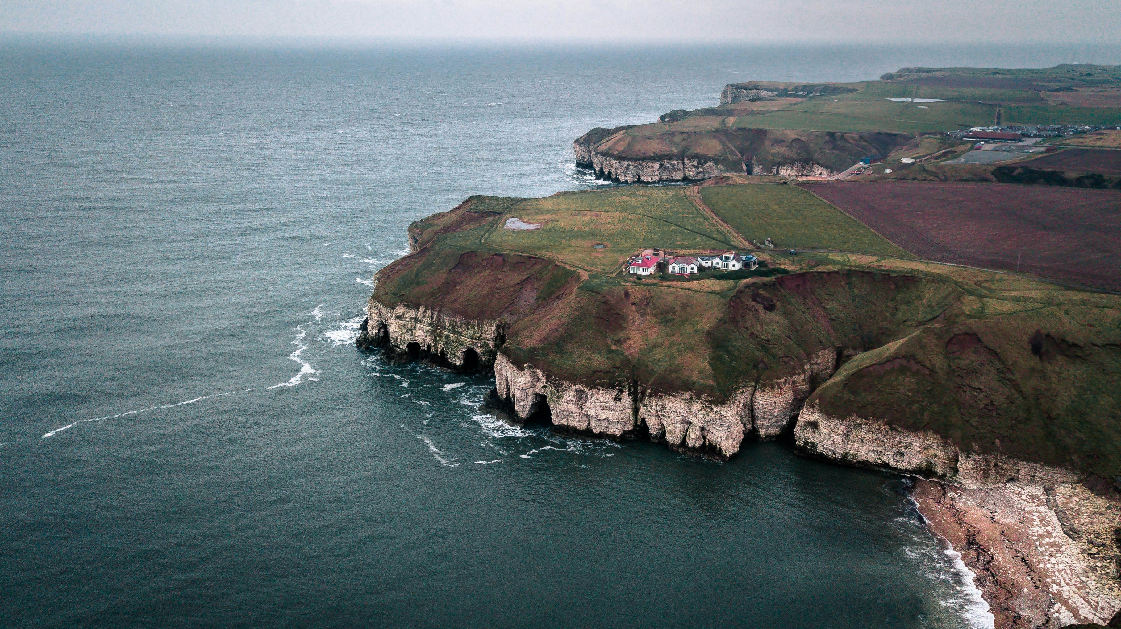 Dramatic white cliffs meeting the vast ocean under a cloudy sky.