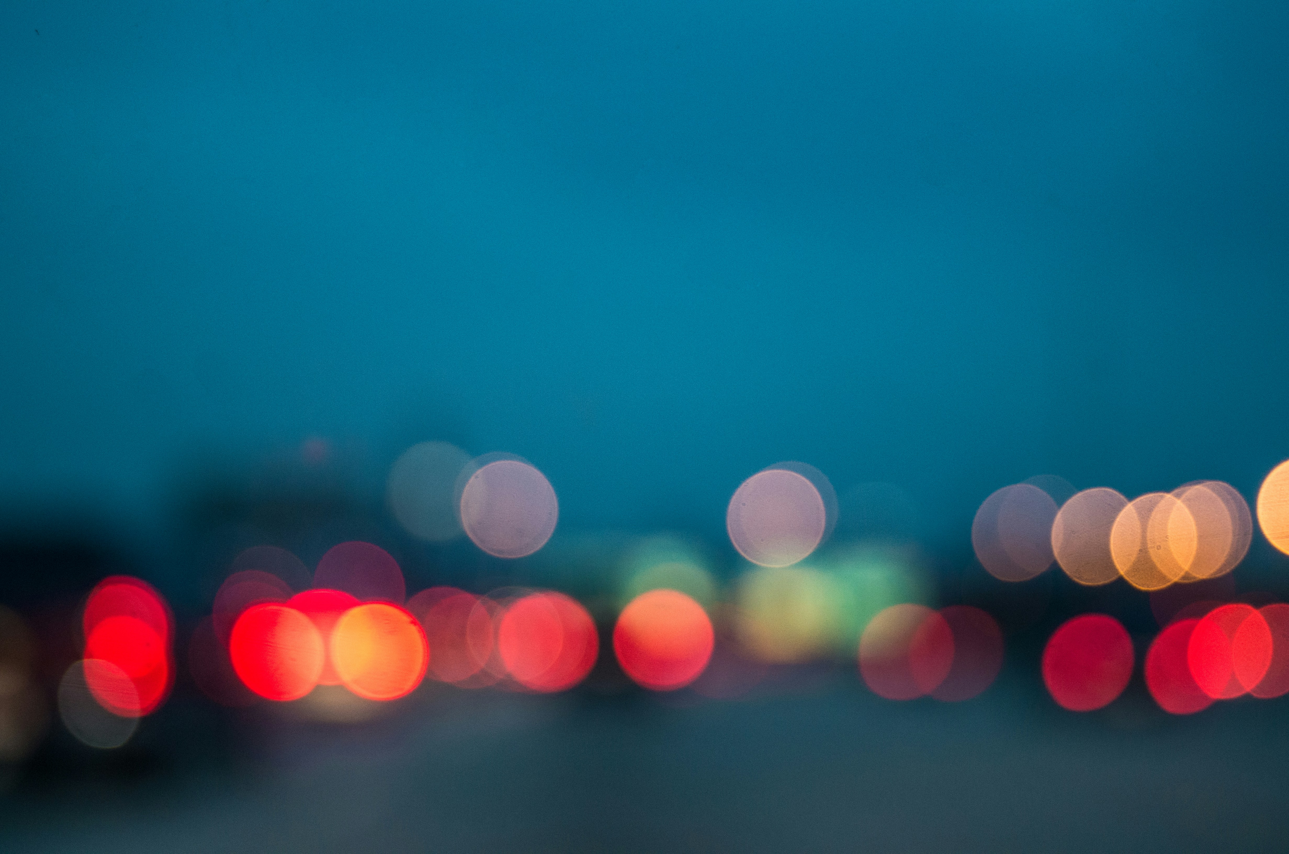 Abstract bokeh effect featuring blurred red and orange lights against a cool blue background, evoking a sense of movement and energy.
