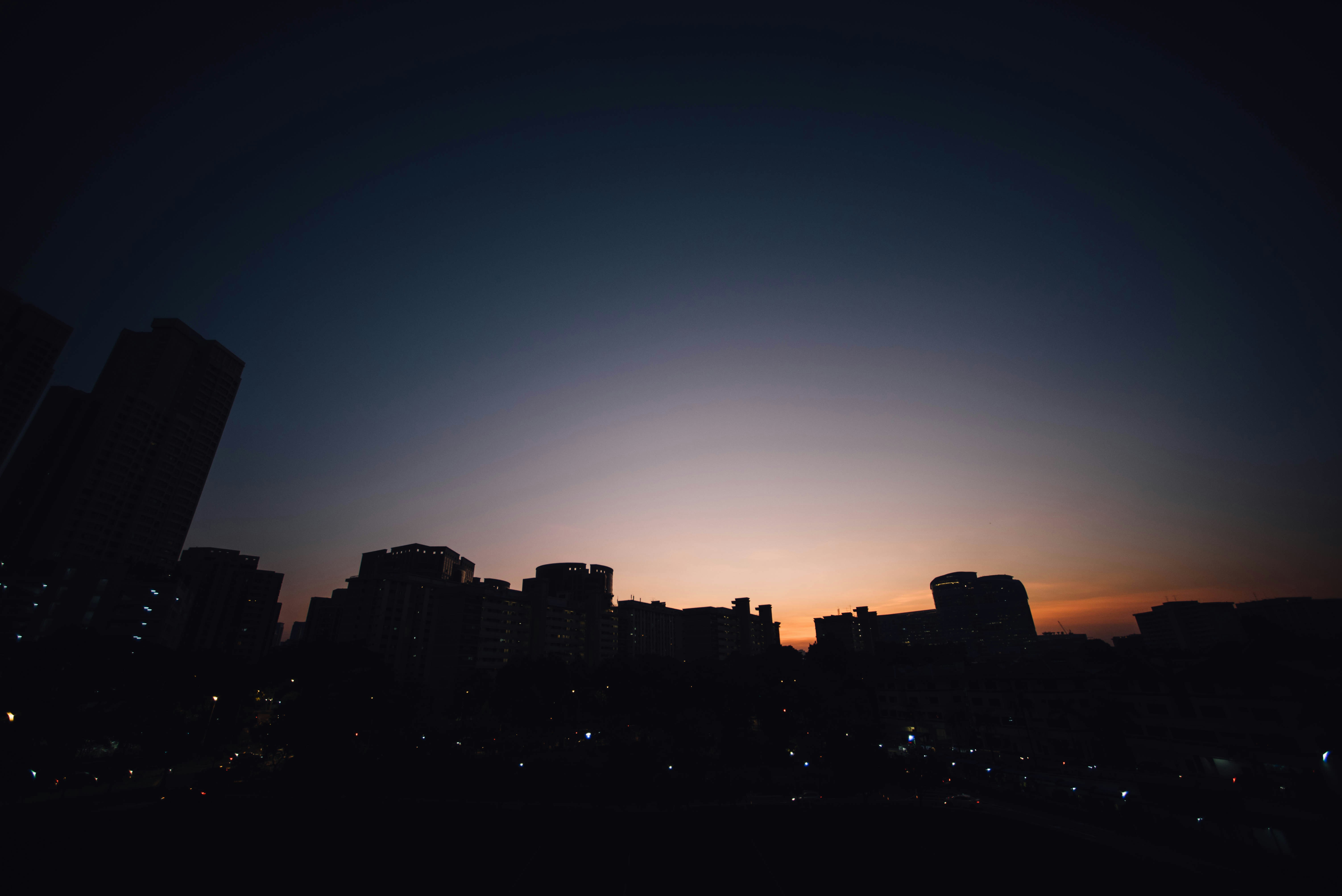 Silhouetted city skyline against a deep blue and orange twilight sky.