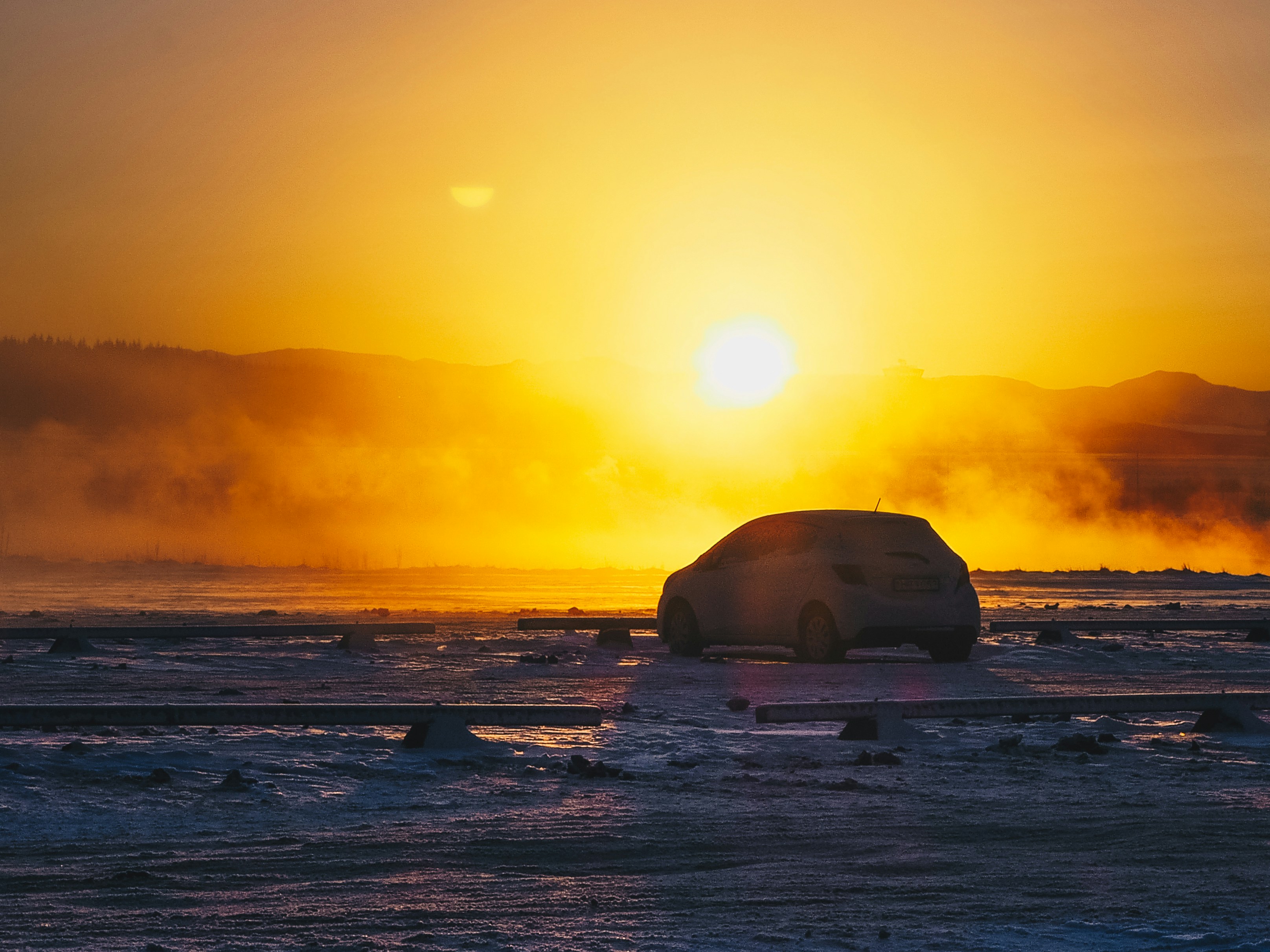 Fiery Horizon Over Snow: The Lone SUV in Backlit Silence