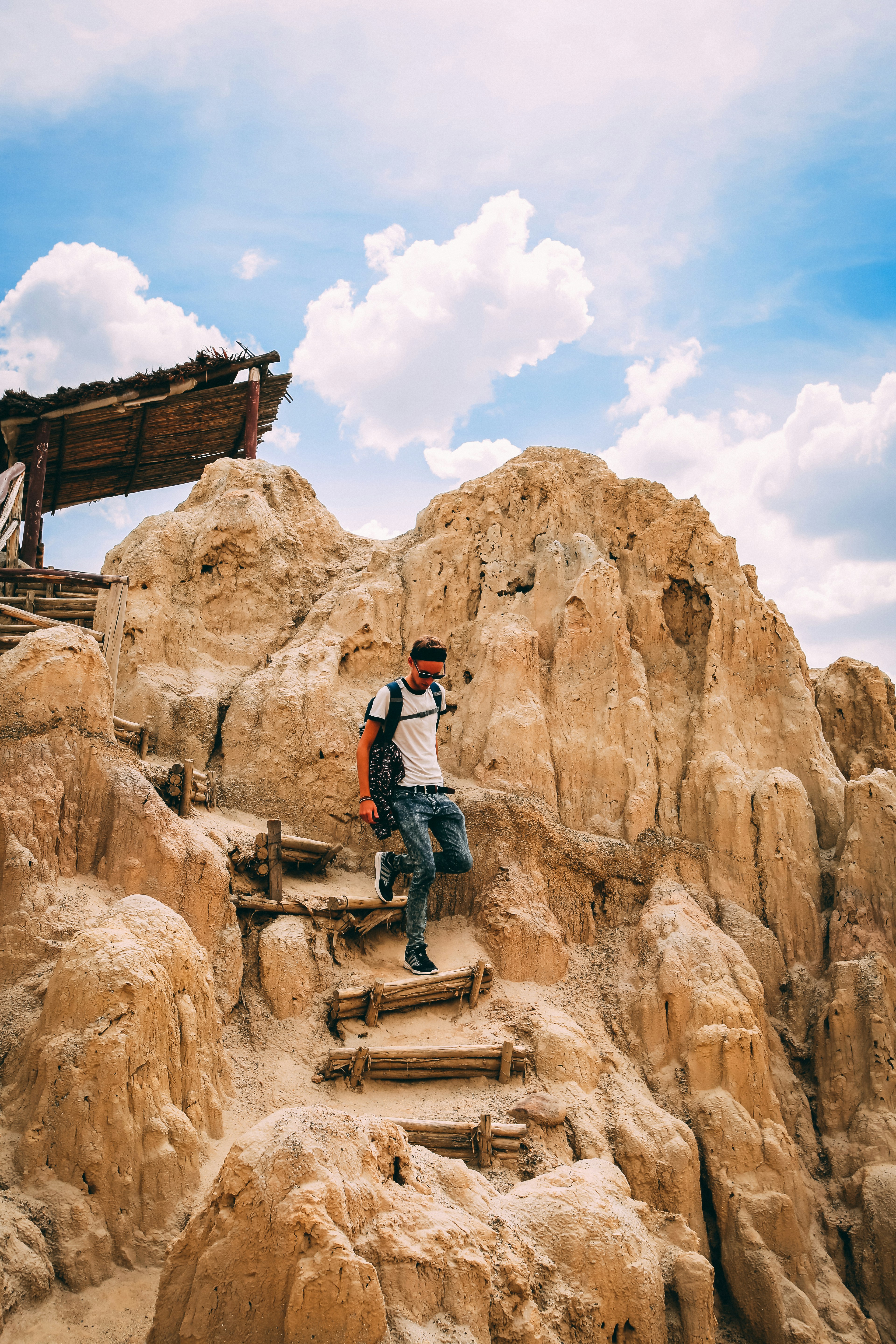 Sunlit Climb: A lone climber negotiates a weathered wooden stair along sun-bleached limestone
