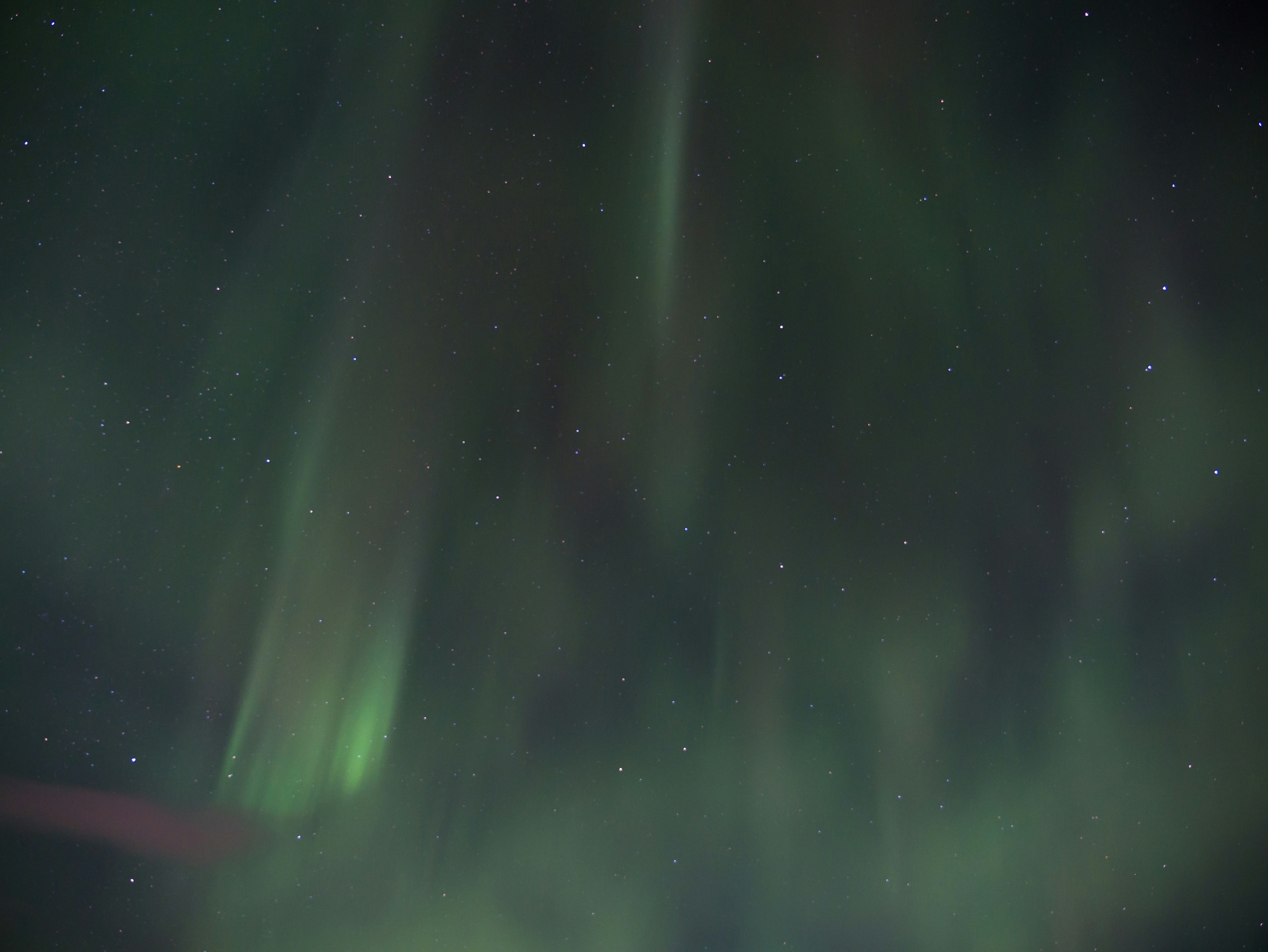 Aurora borealis drapes emerald curtains across a star-filled night sky. A still photograph capturing the ethereal glow and distant stars.