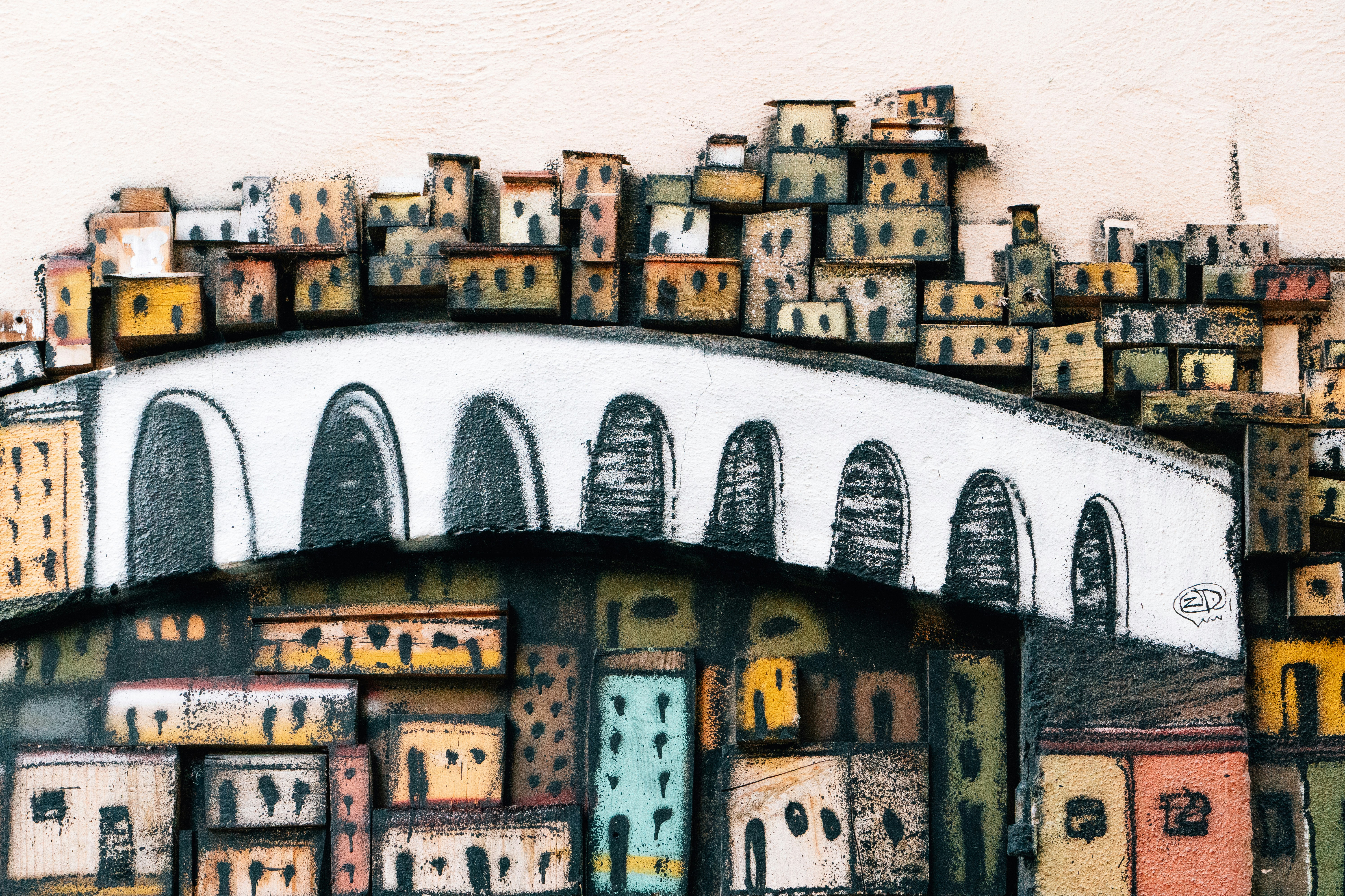 Vibrant mural depicting a bridge surrounded by a colorful cityscape, showcasing an artistic interpretation of urban life.