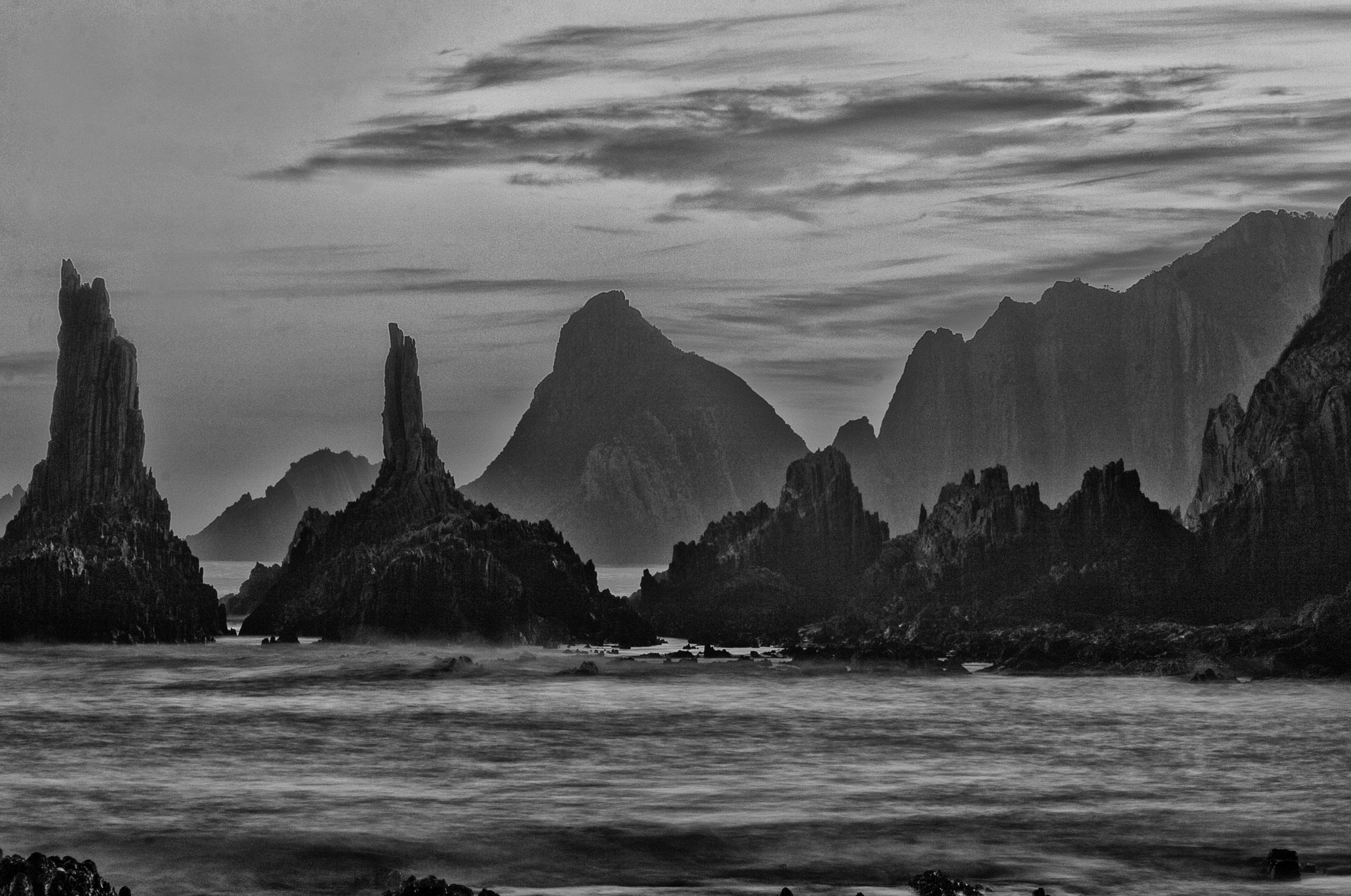 Grayscale photo of rock formations on body of water photo – Free Grey ...
