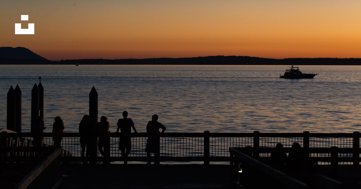Silueta De Personas De Pie En El Muelle Durante La Puesta Del Sol Foto