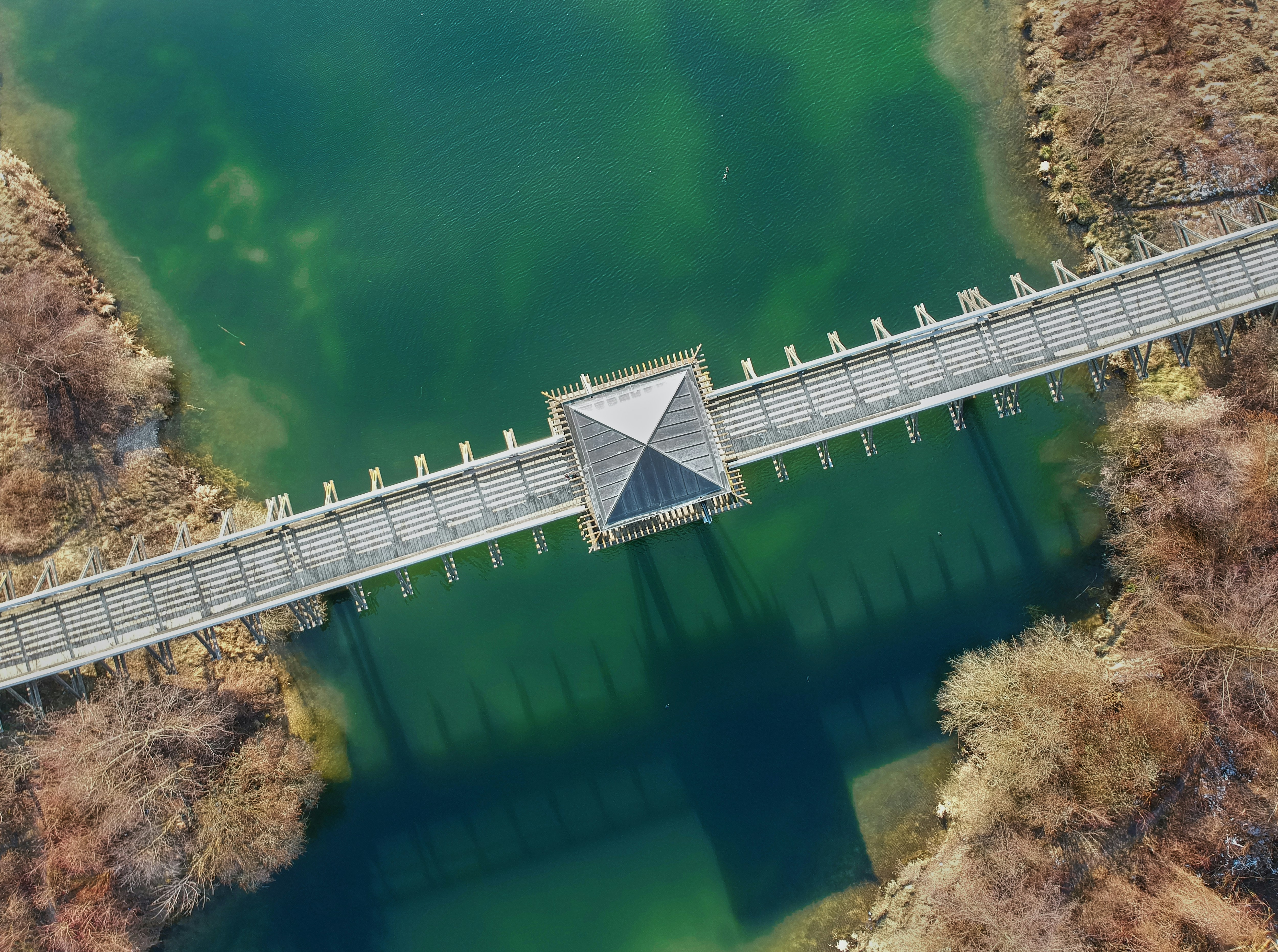 Top angle photo of gray concrete bridge over green water taken at ...