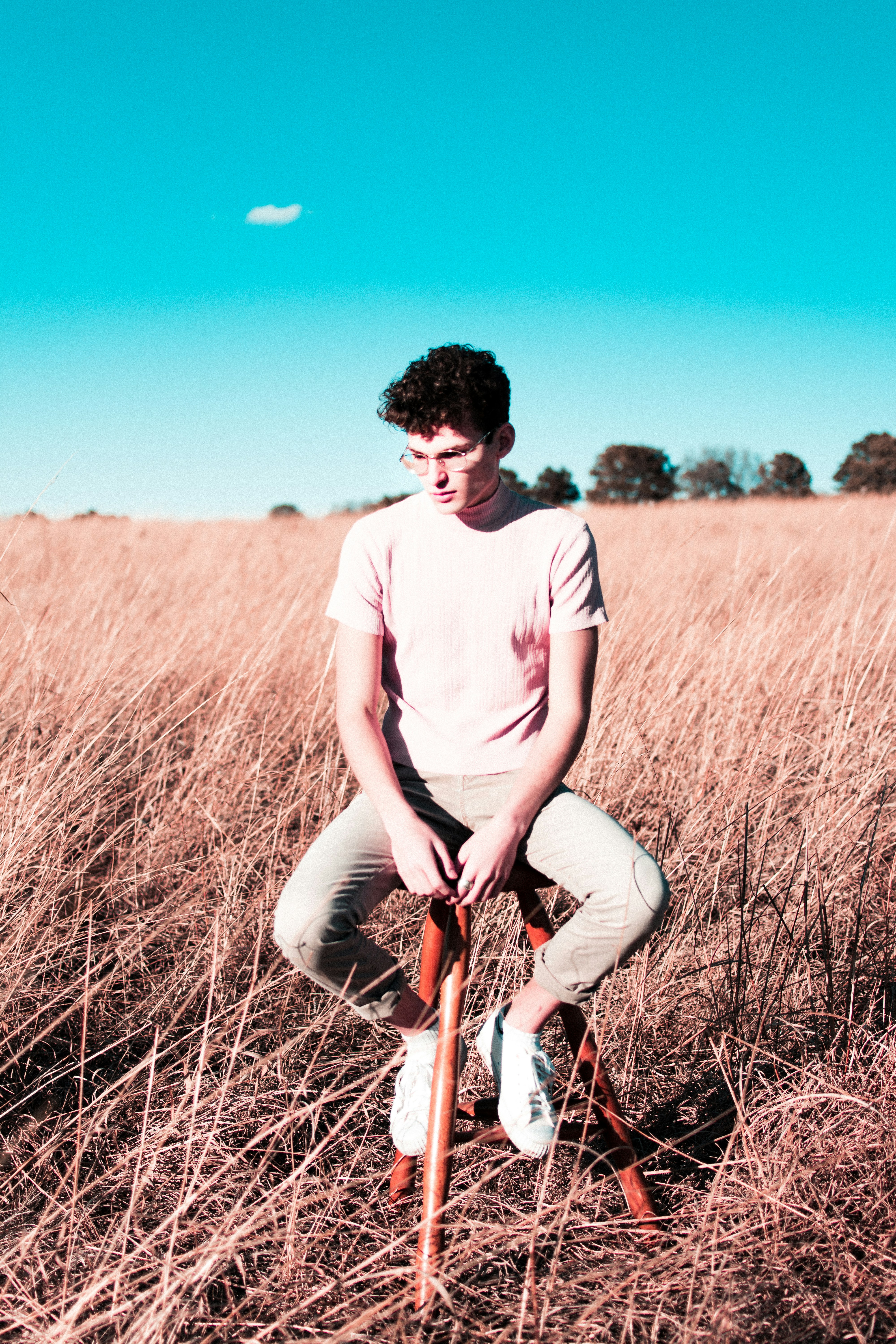 Man sitting on red stool on brown field grass during daytime photo ...