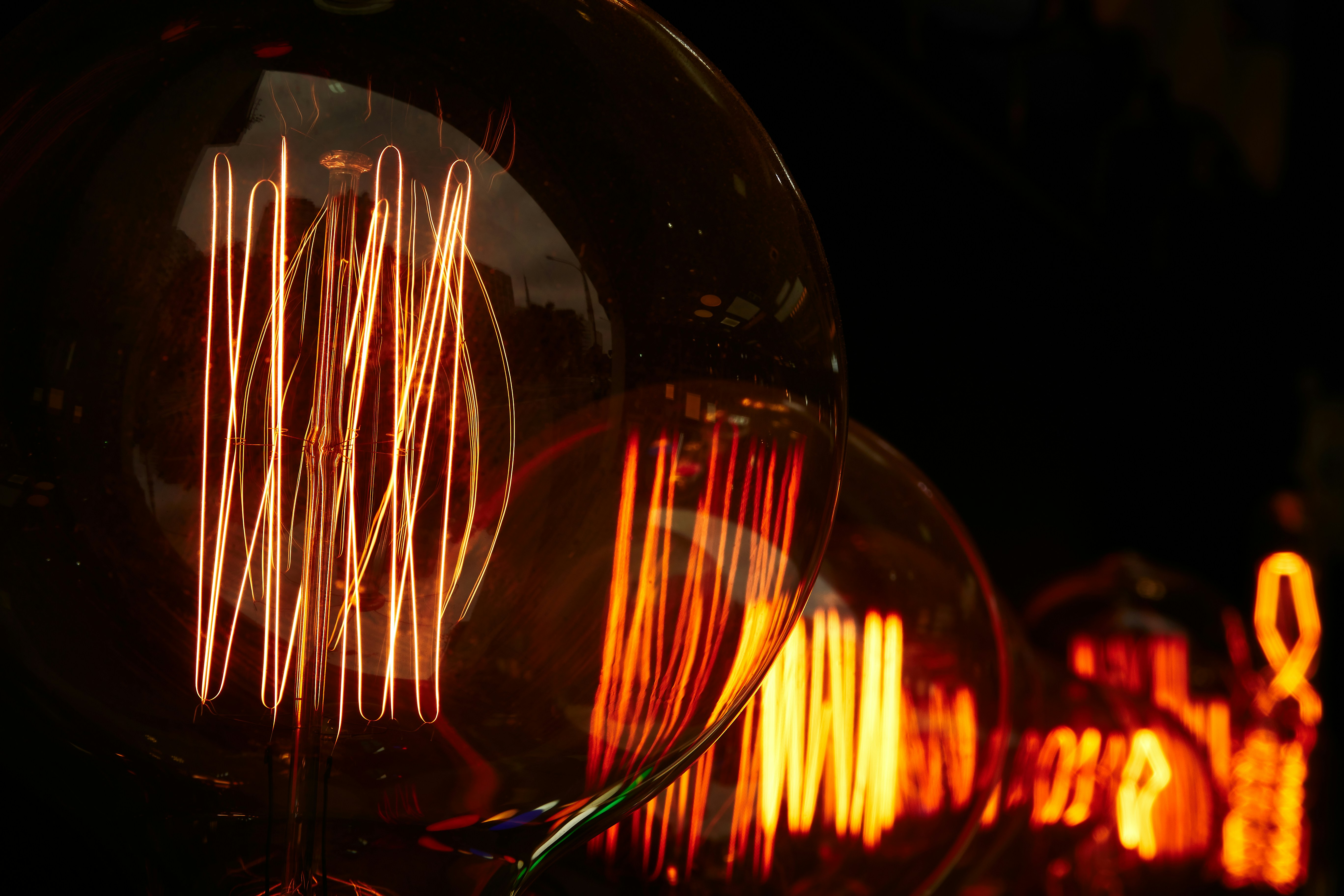 Close-up of vintage light bulbs showcasing intricate filament designs and warm glow against a dark backdrop.