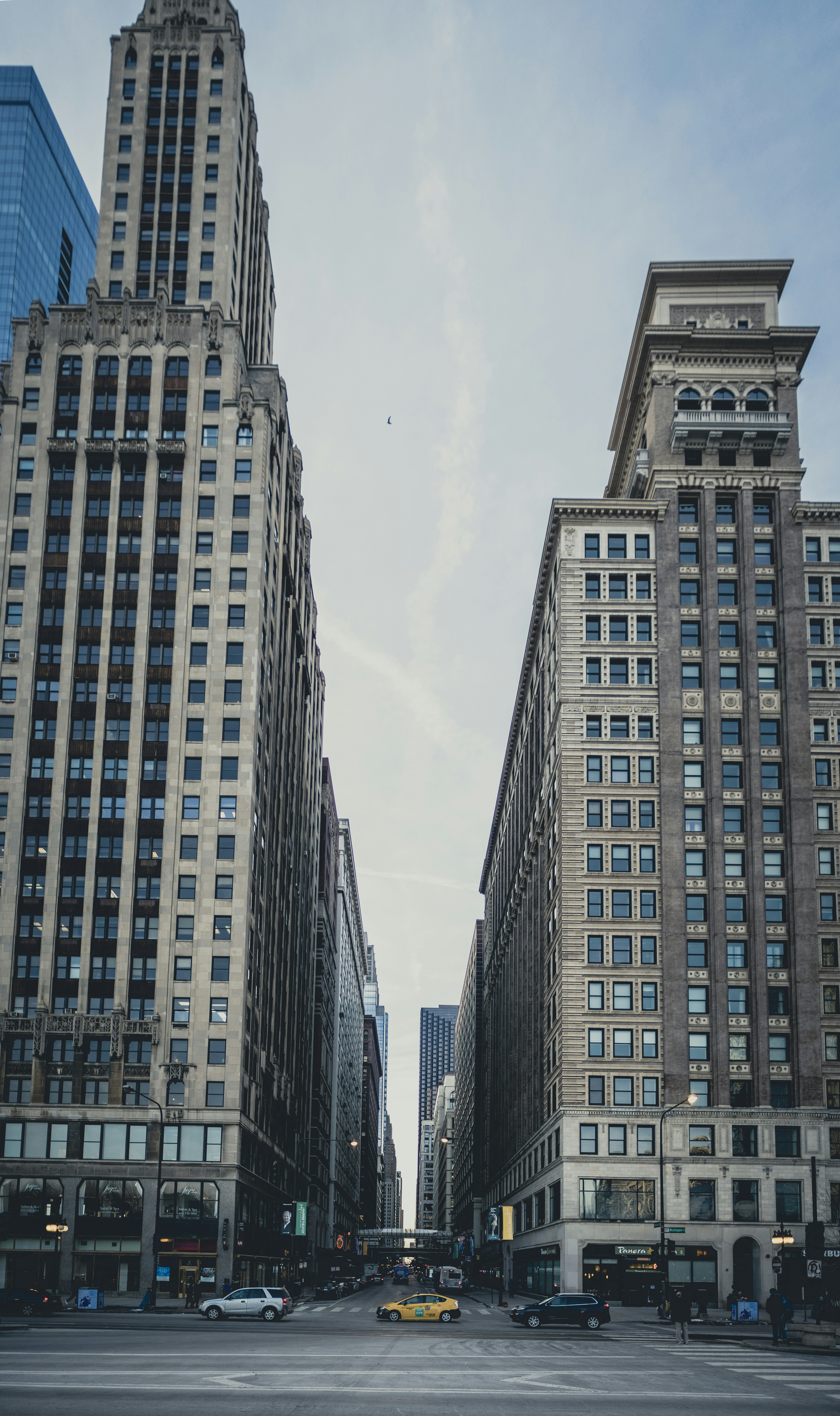 Historic buildings flanking a busy intersection in an urban setting, with a yellow taxi navigating through the scene.