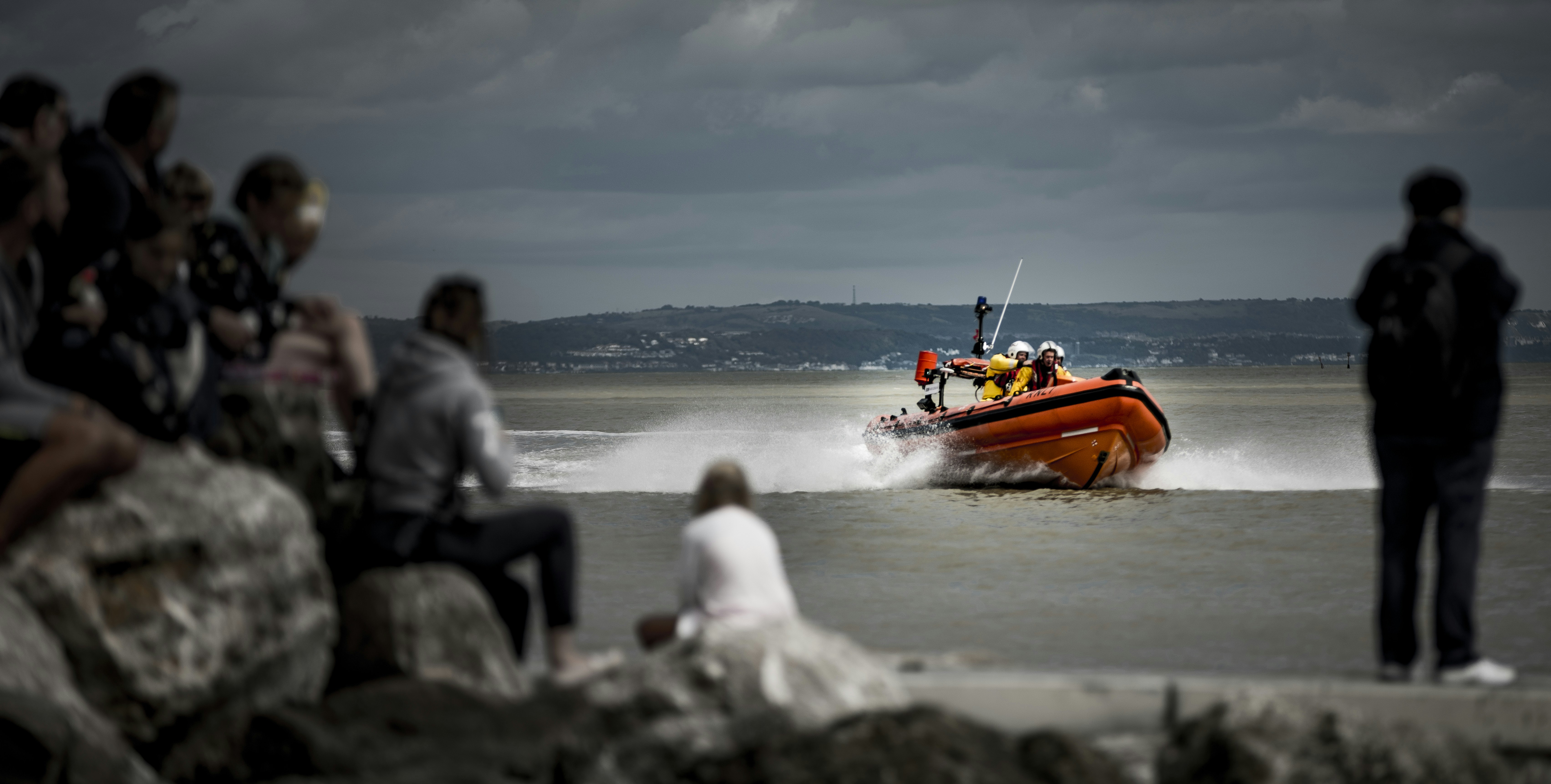 Racing Wave: Lifeboat Surge Silhouettes the Shoreline Crowd