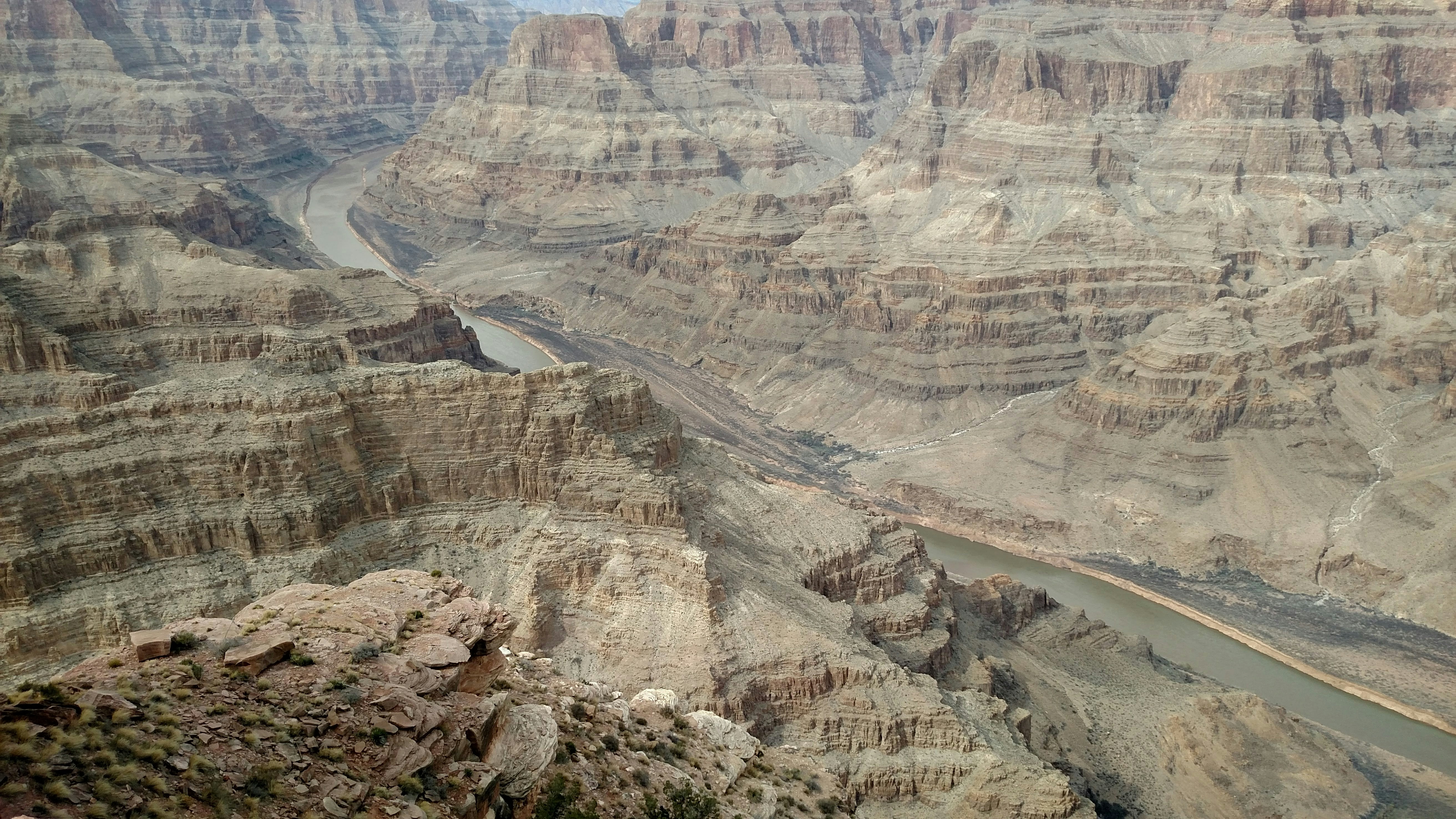 Expansive canyon with a river winding through rugged terrain under a clear sky.