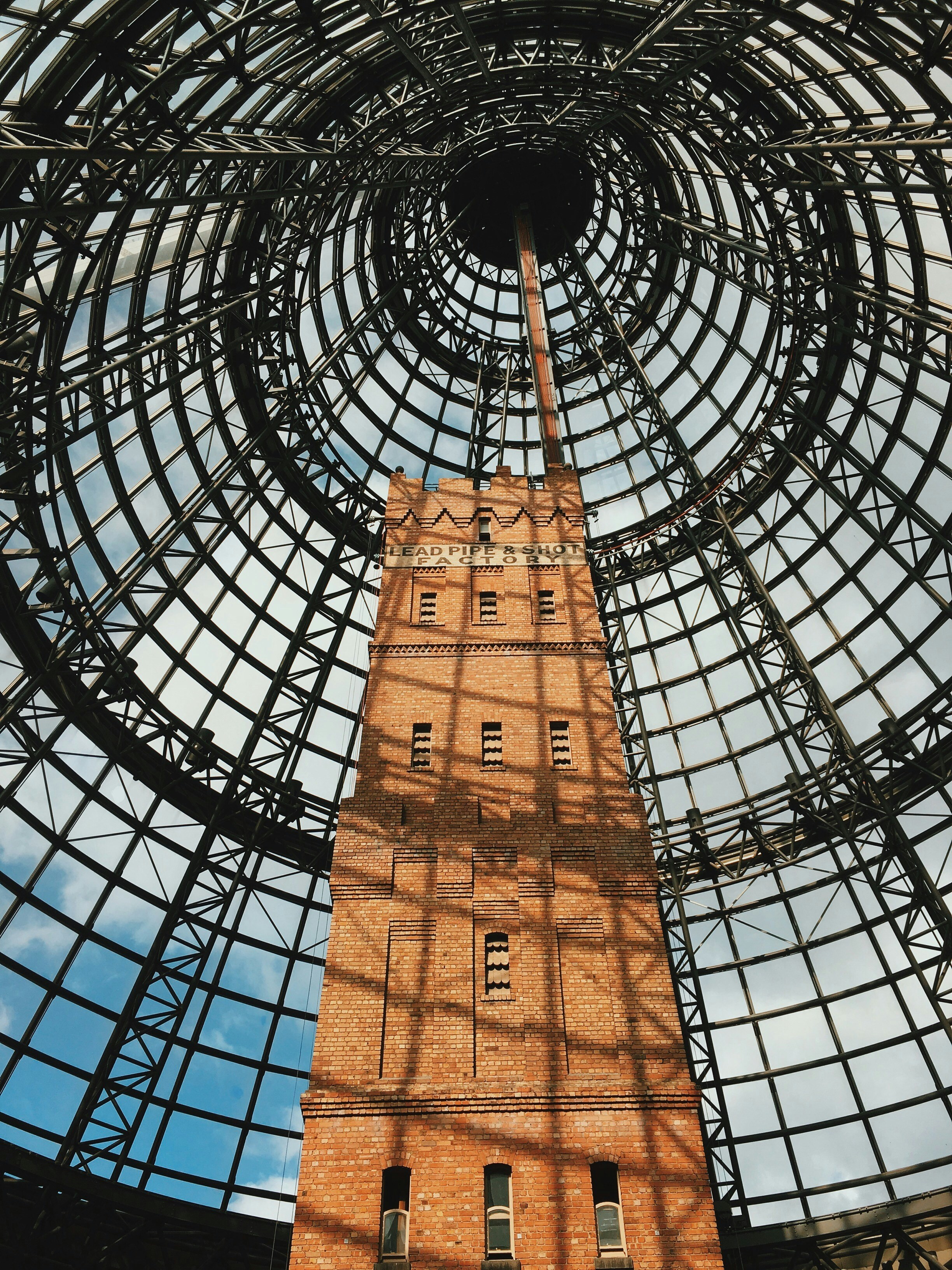Brick Spire Rising Through a Glass Lattice