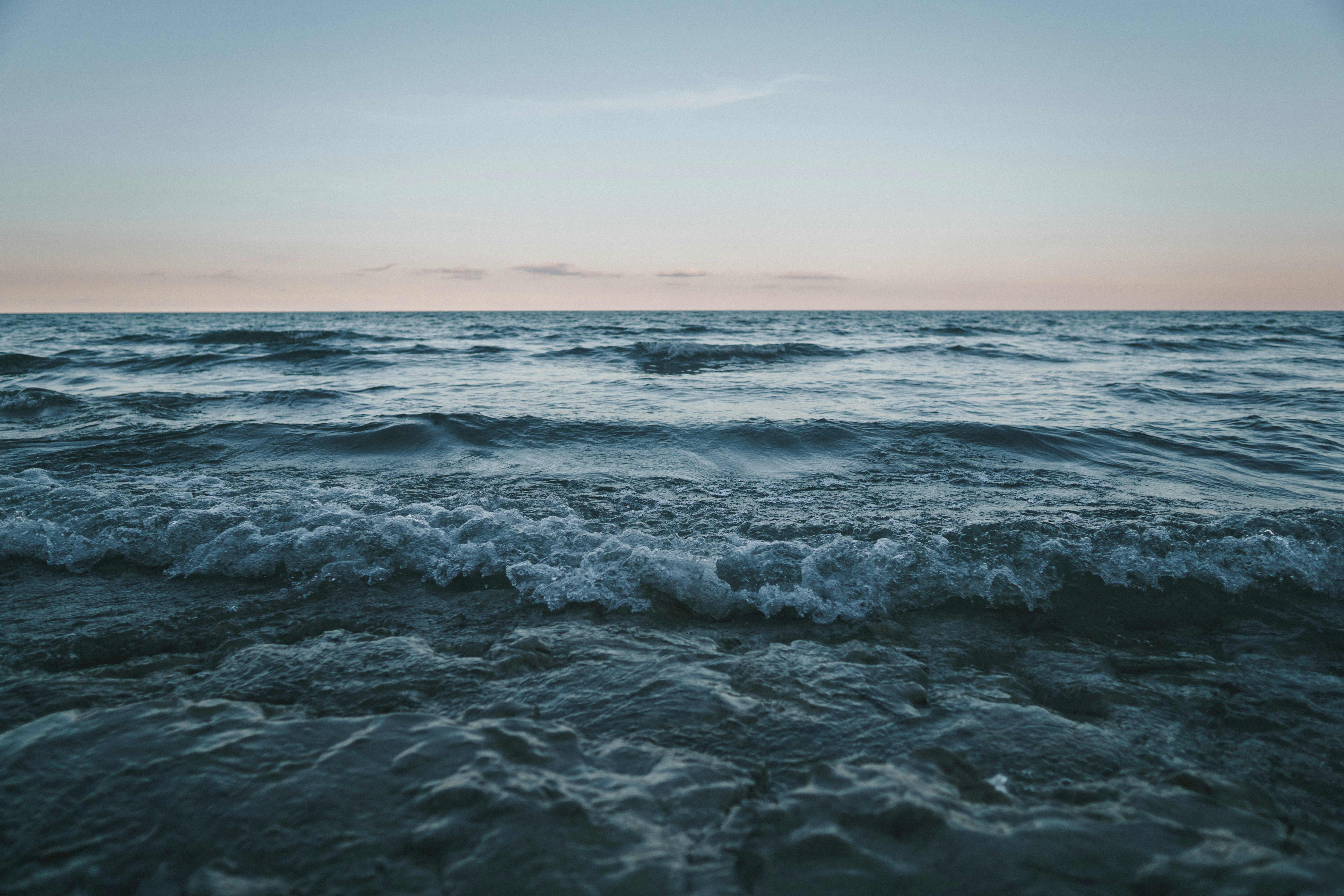 Gentle waves lapping at the shore under a pastel sky at dusk.