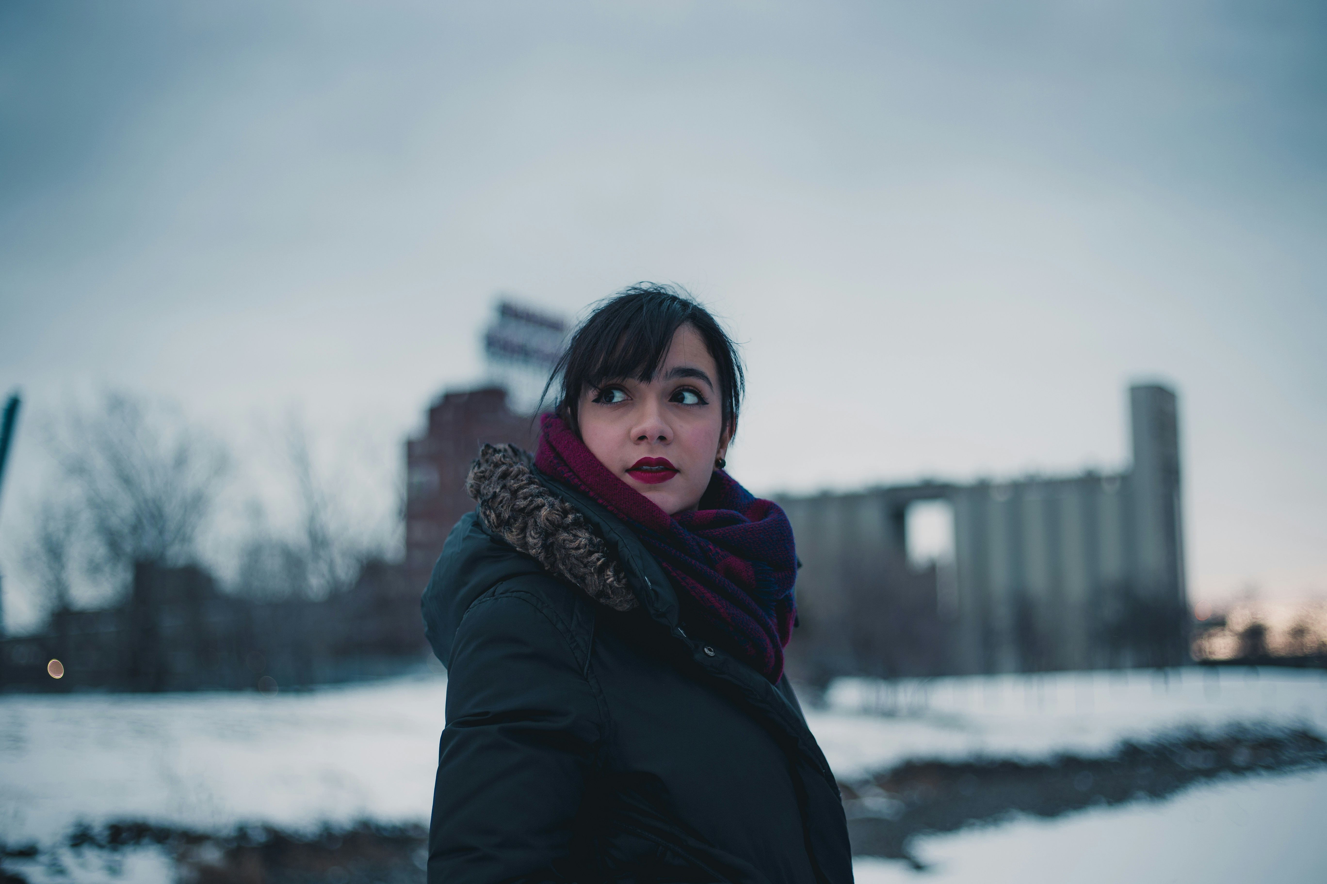 Face in the Frost: Portrait Amid Snow and Silhouetted Industry at Dusk