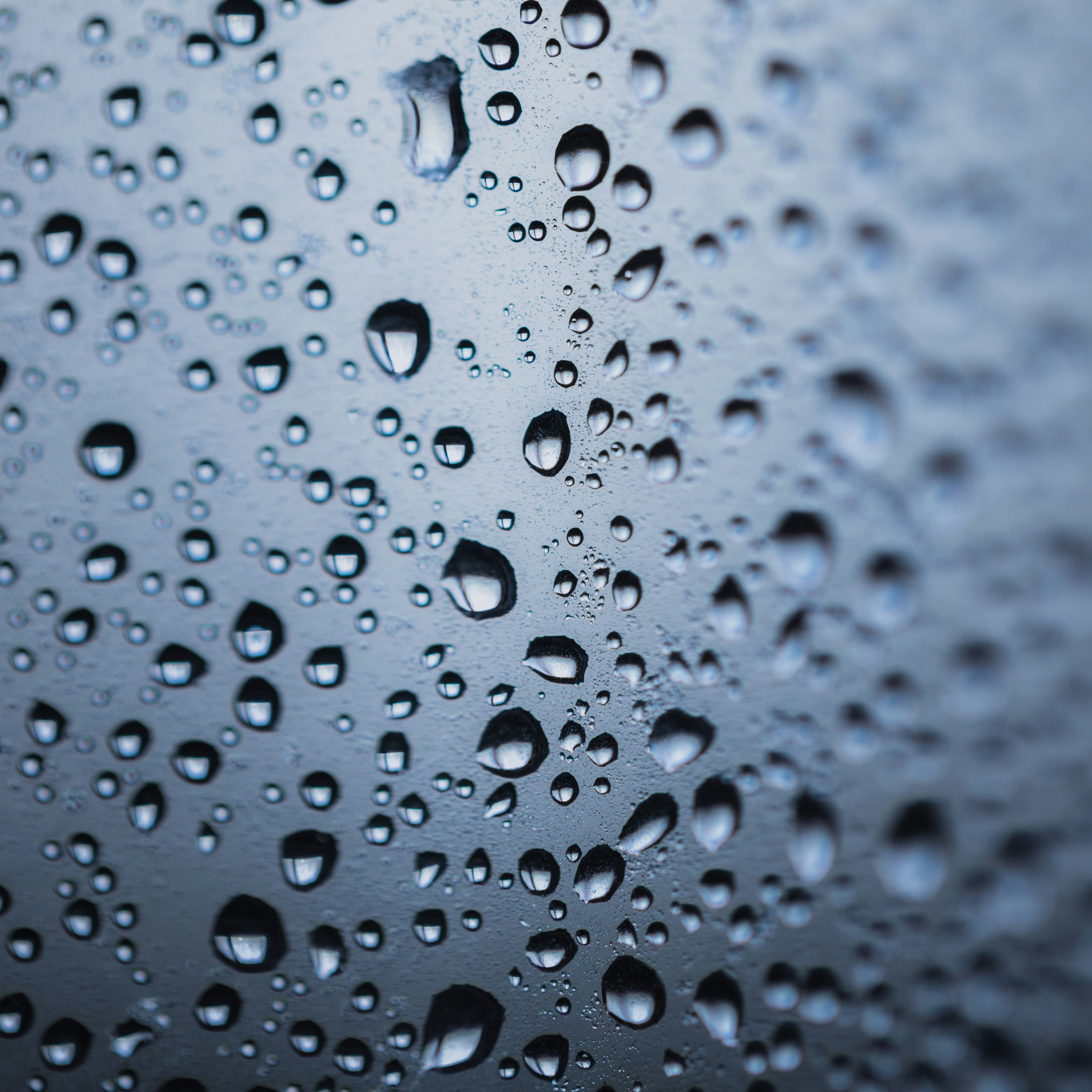 Close-up view of water droplets on a surface, showcasing intricate patterns and reflections. The image emphasizes the beauty and complexity of water in its natural state.