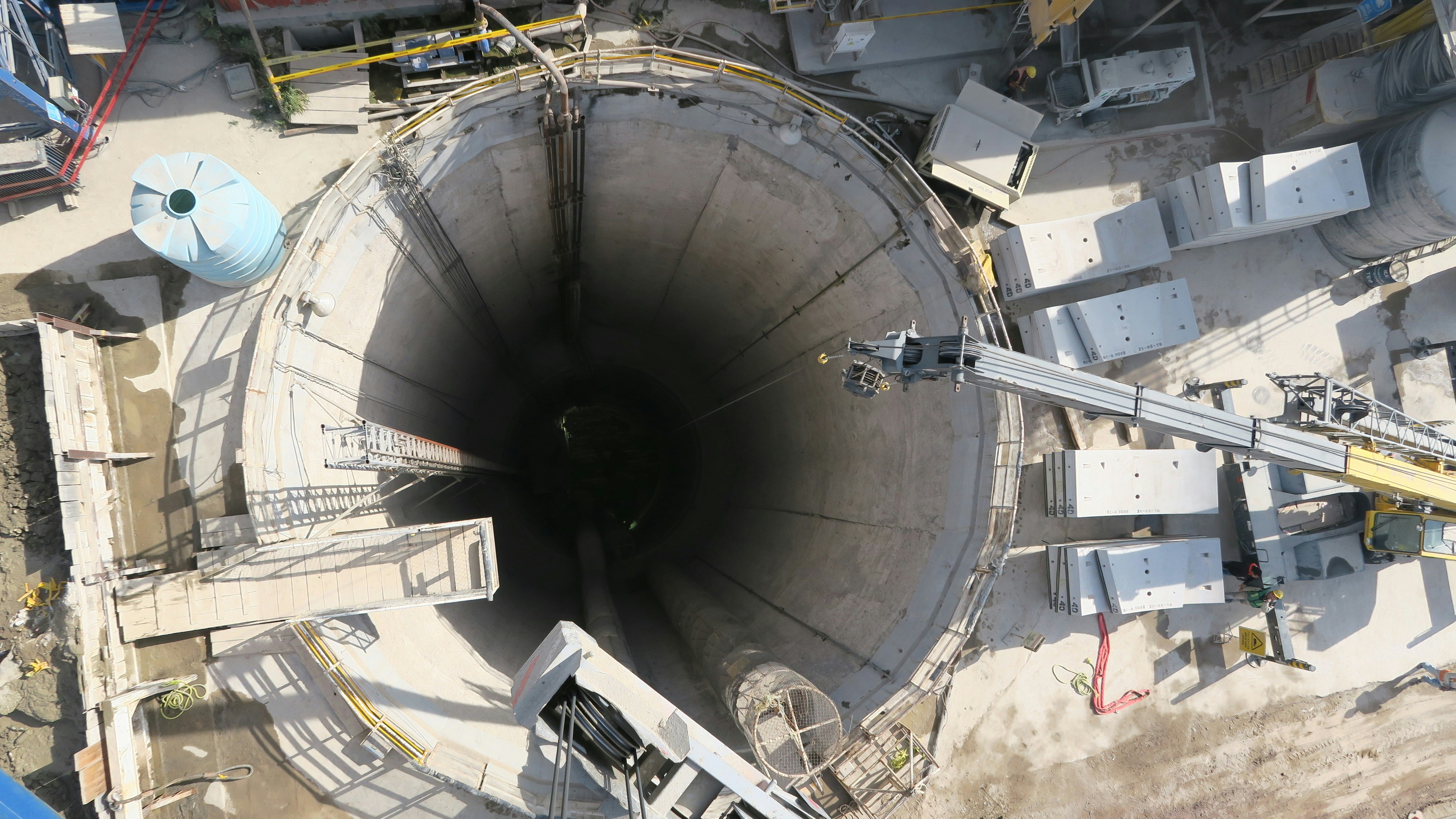 Aerial view of a large construction site with a deep circular pit surrounded by machinery and equipment.