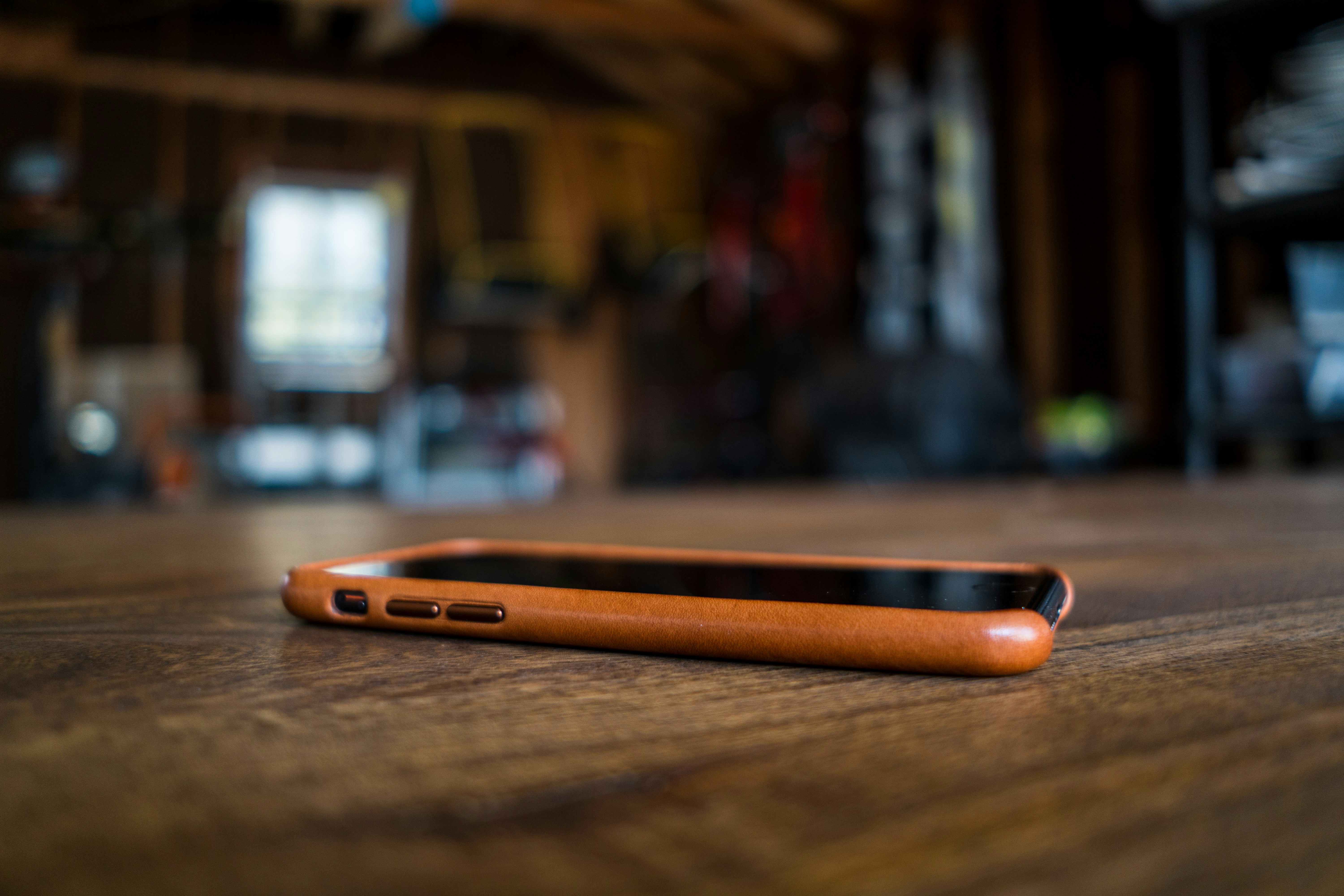 Low-angle close-up: leather-cased smartphone resting on weathered wood