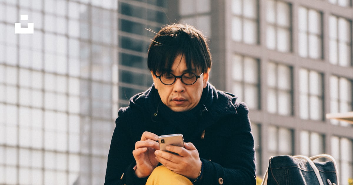콘크리트 벤치에 앉아 스마트폰을 사용하는 남자 사진 Unsplash의 무료 사업 이미지