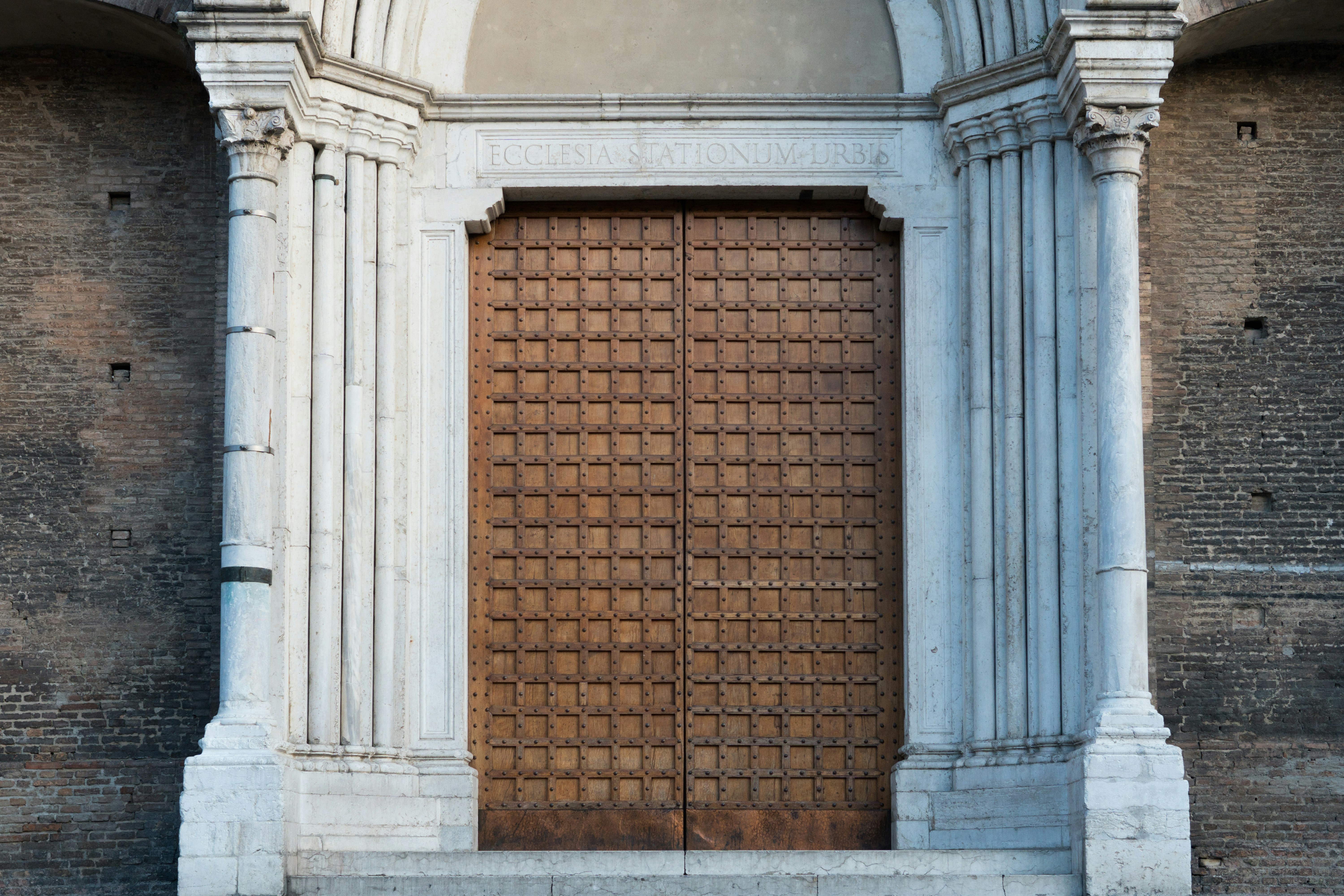 Ornate wooden door framed by grand stone columns on a historic building facade.