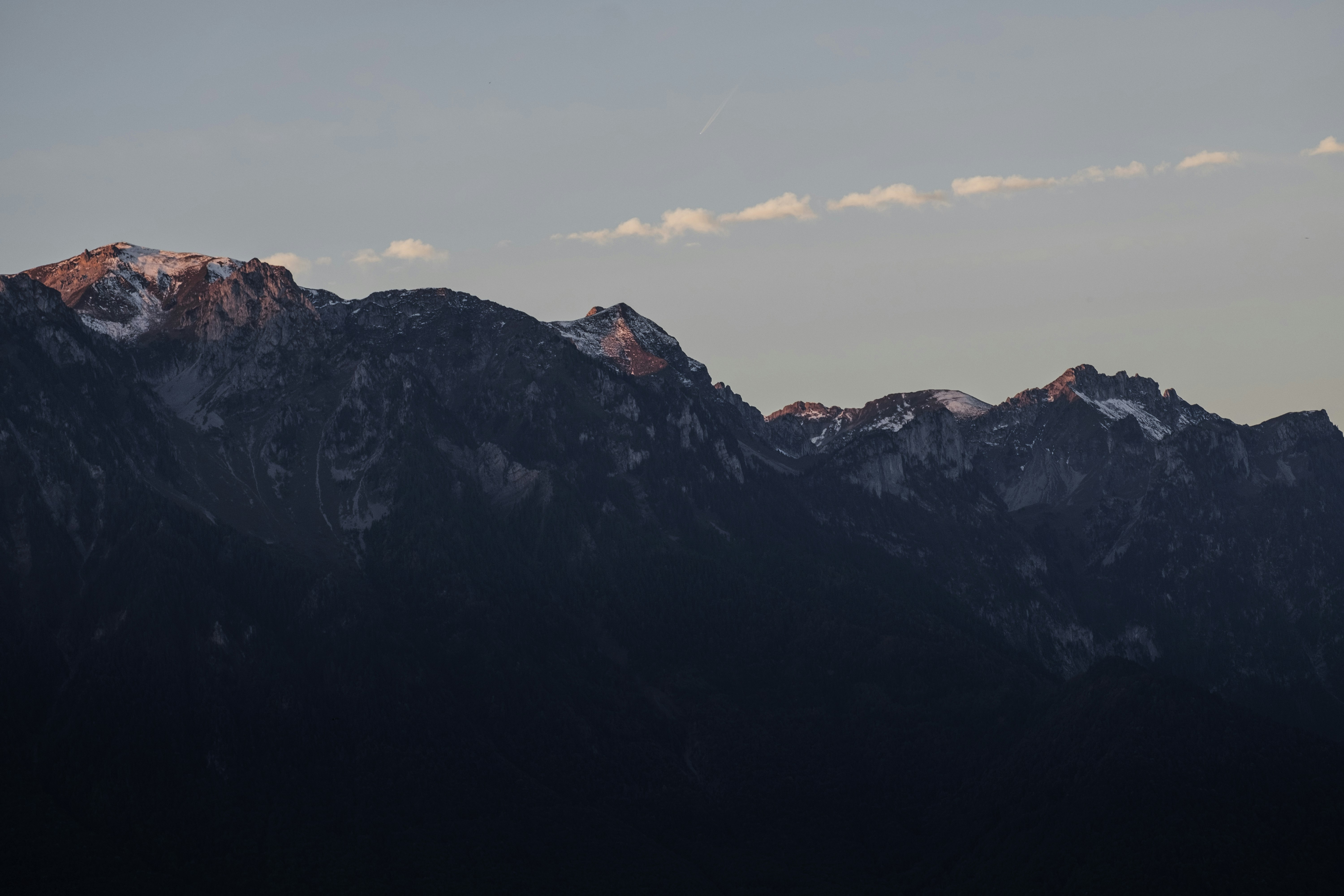 Mountain range bathed in soft pink light under a clear sky.