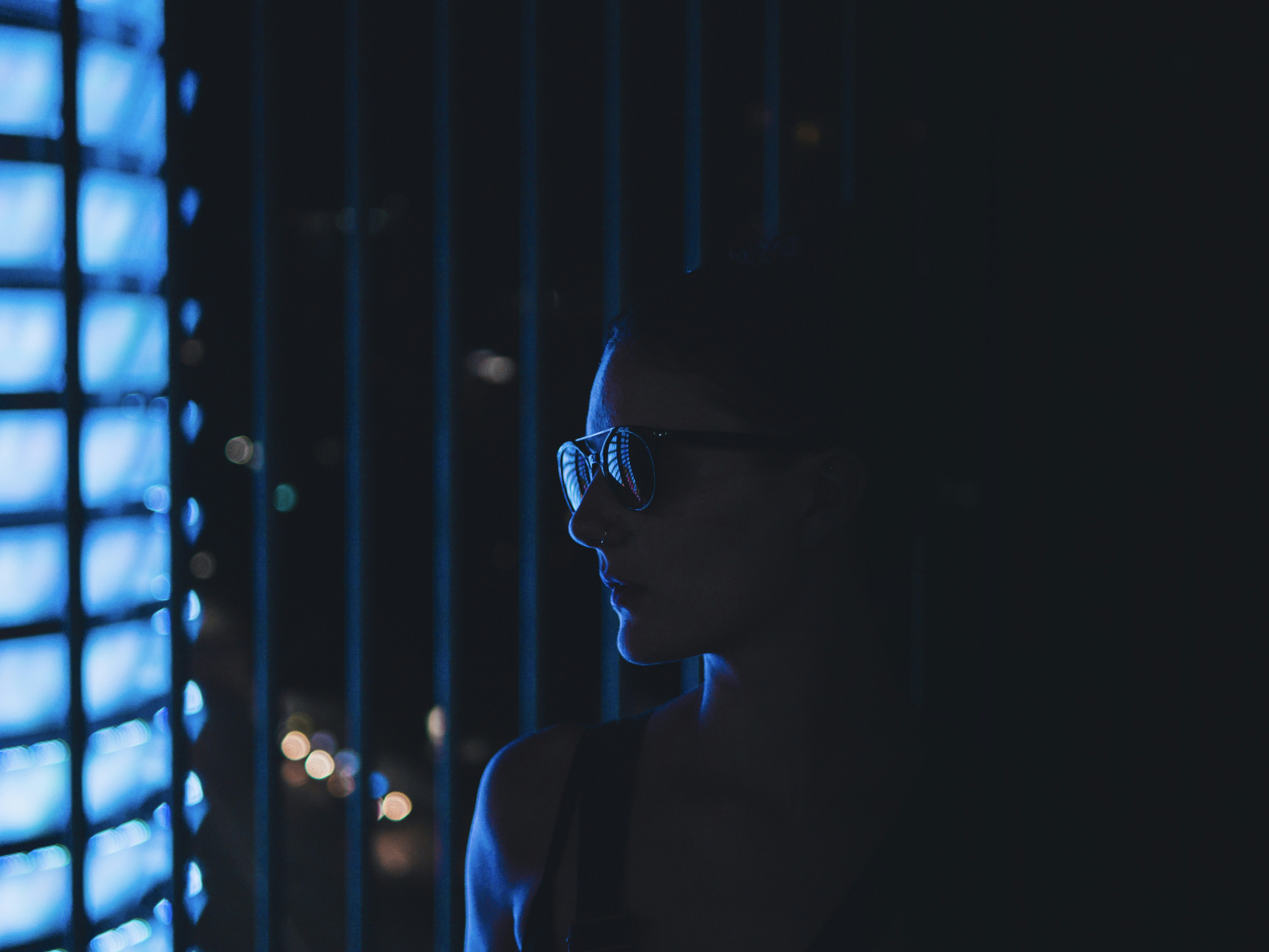 Person in silhouette with neon blue light casting shadows in a darkened carpark.