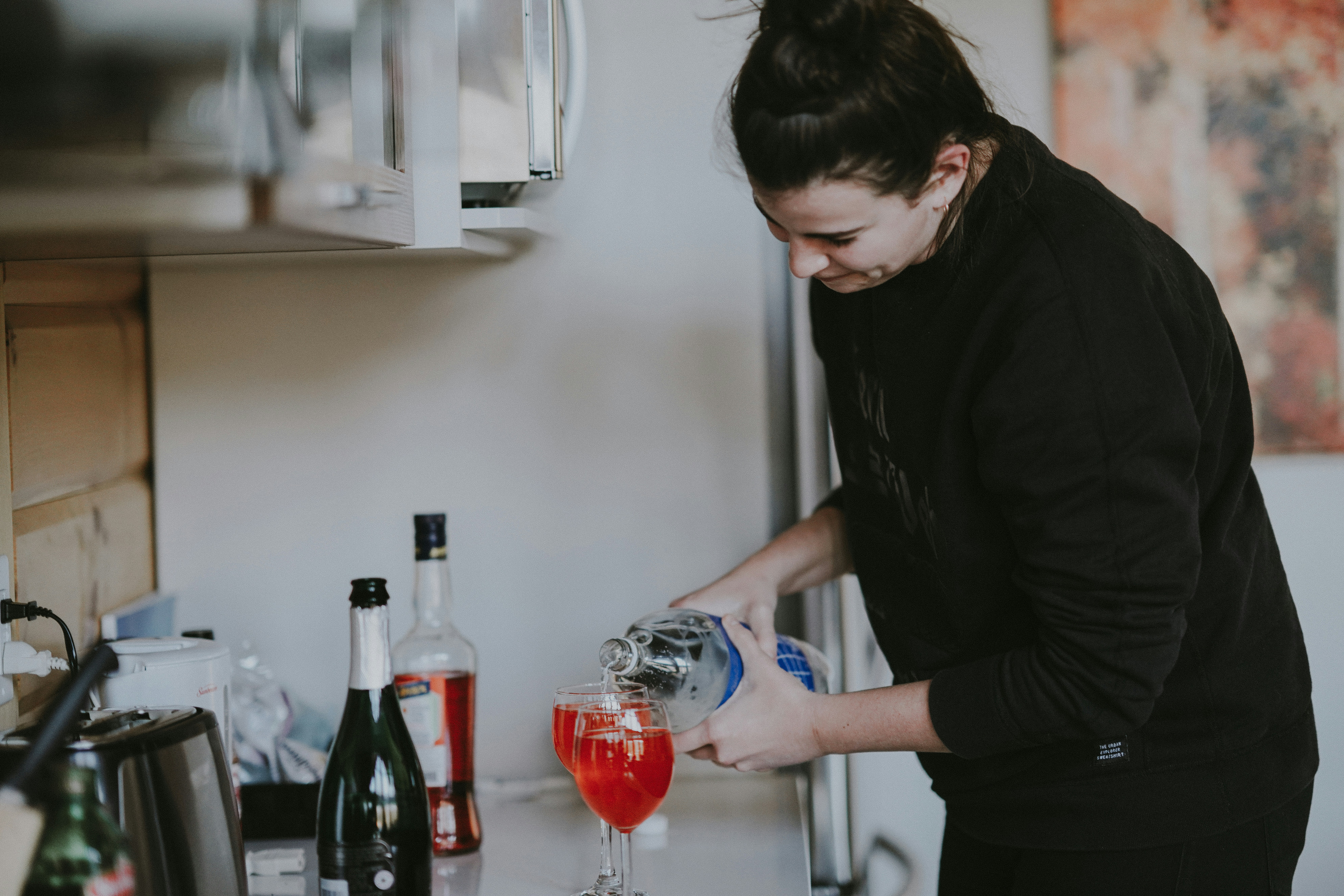 Woman making a cocktail | woman holding clear glass wine bottle photo
