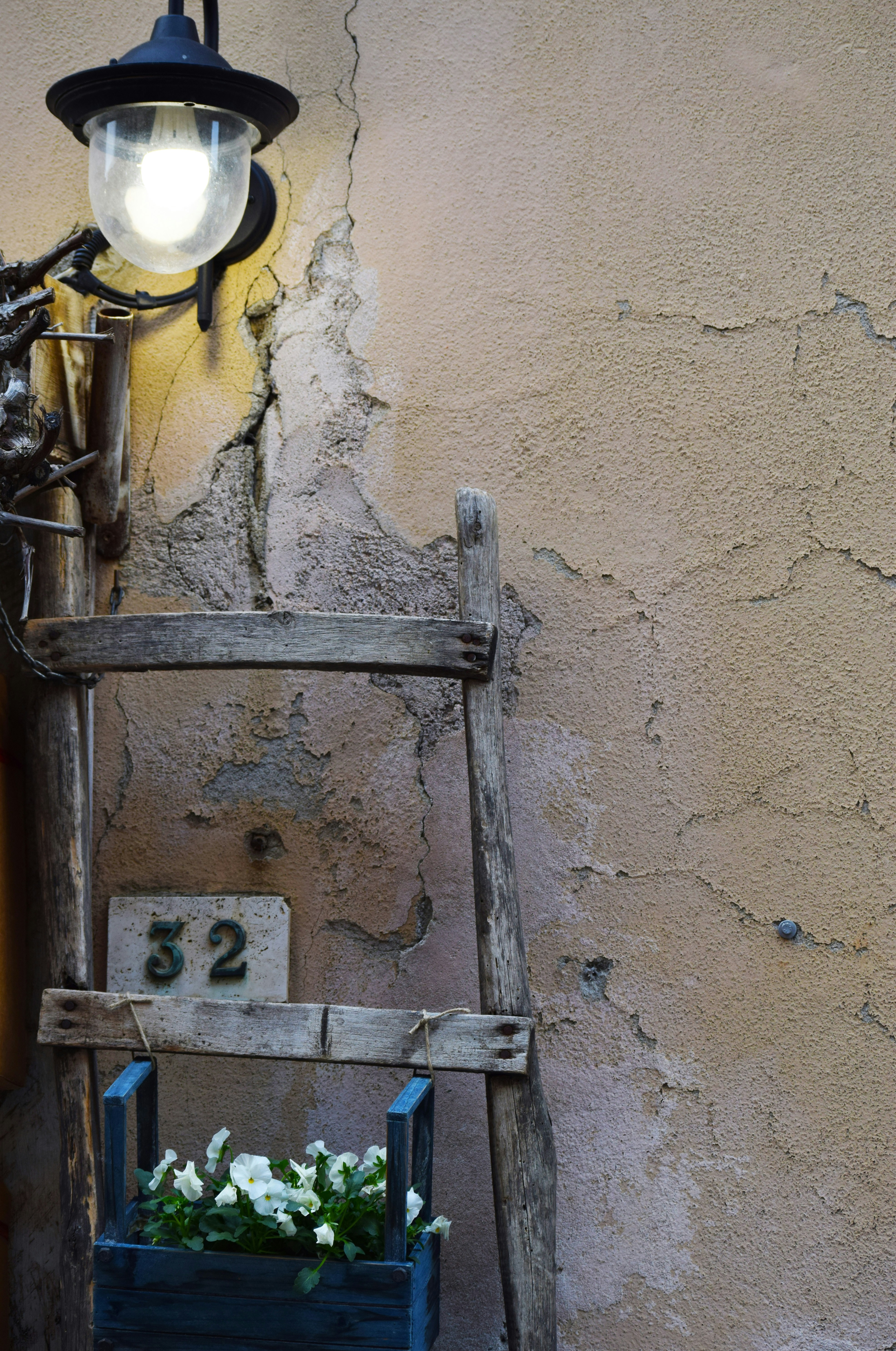 Lantern Glow on a Weathered Wall: Wooden Frame and Blue Planter