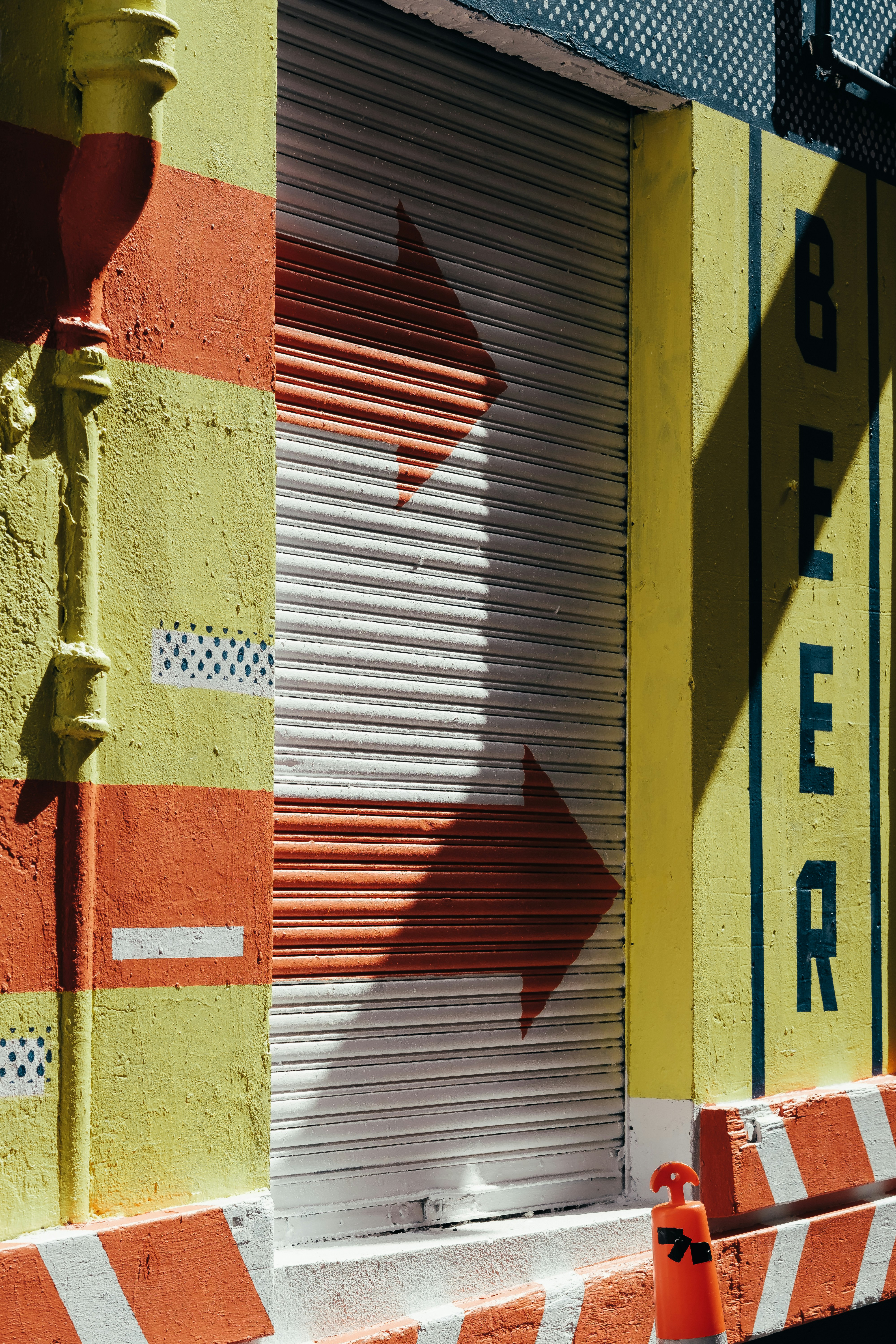 Vibrant mural featuring arrows and bold typography against a textured wall, highlighting an urban aesthetic. A playful interplay of colors and shapes creates a dynamic visual experience.