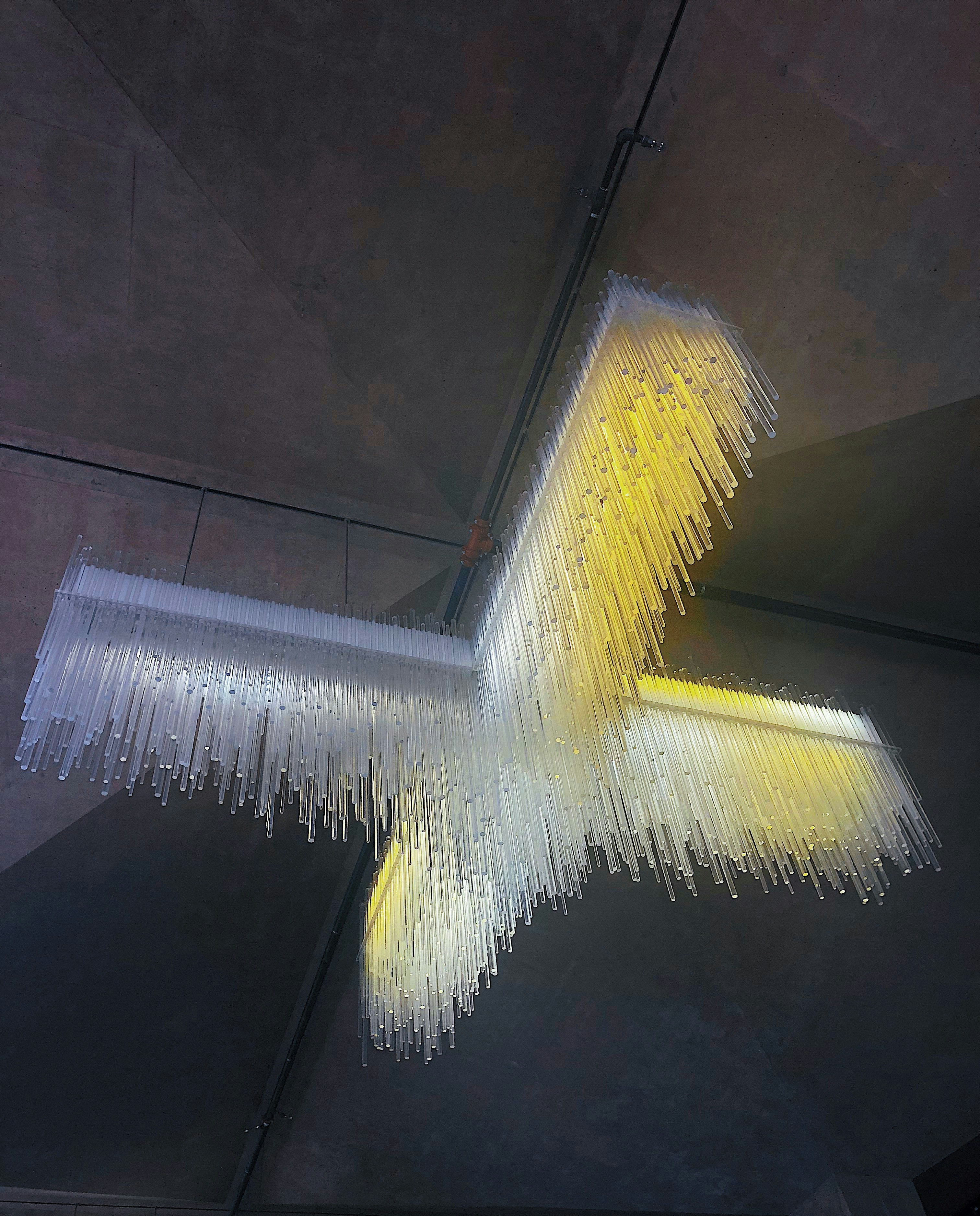 Axis of Light: A glass-rod chandelier formed into a luminous cross