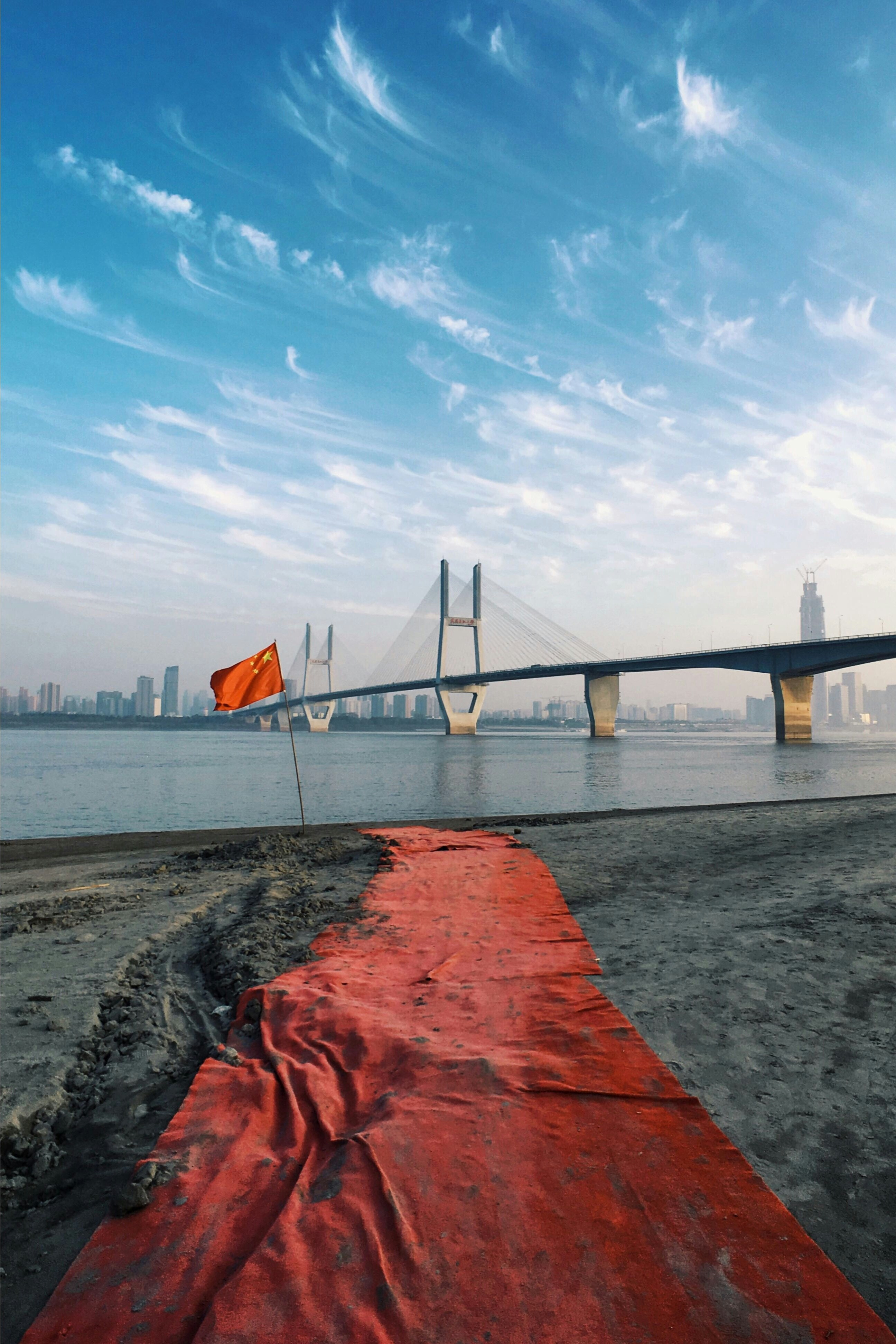 Scarlet Path to the City: a riverbank lead-in to a sweeping cable-stayed bridge