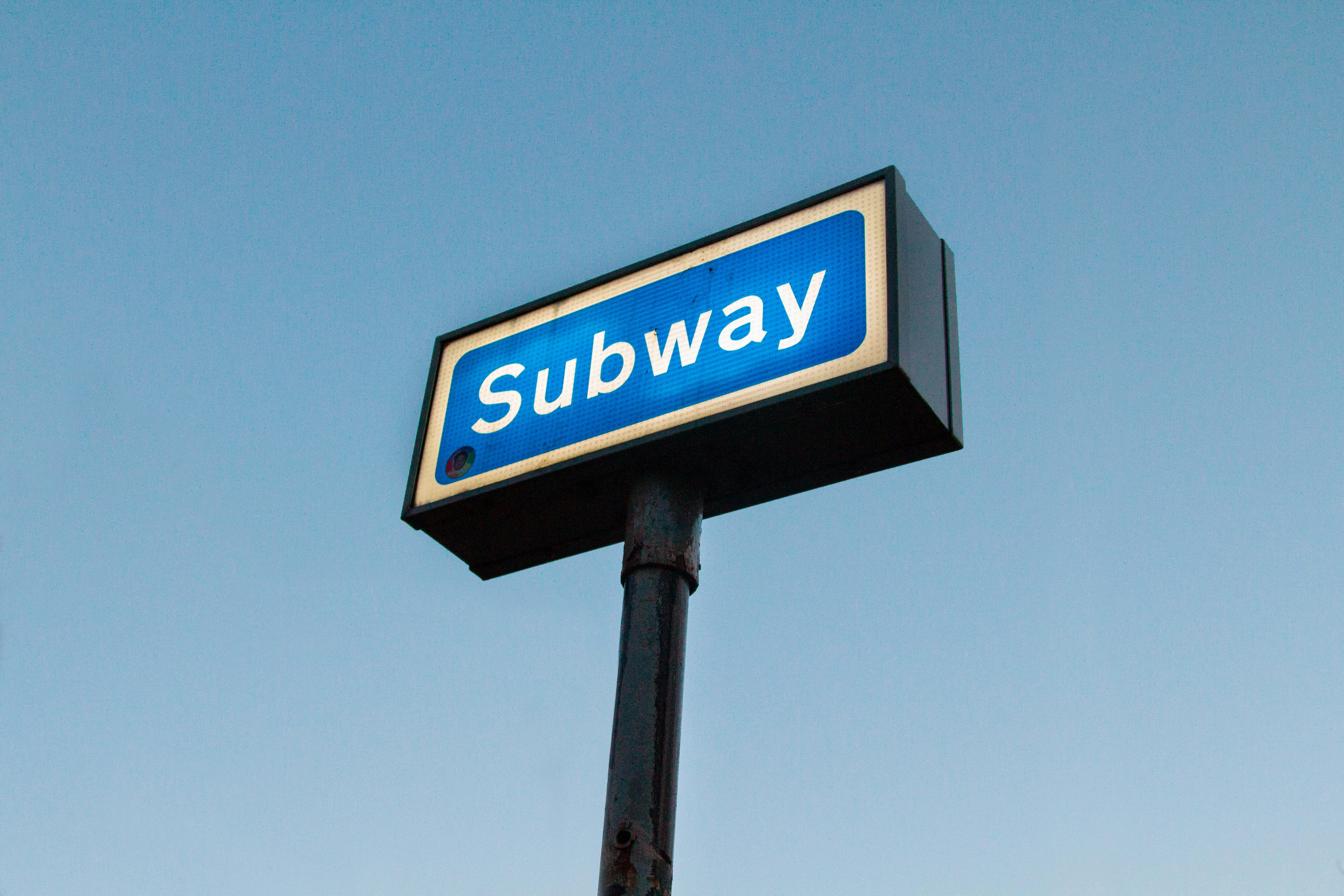 Illuminated Subway sign against a clear blue sky, guiding travelers to their next destination.